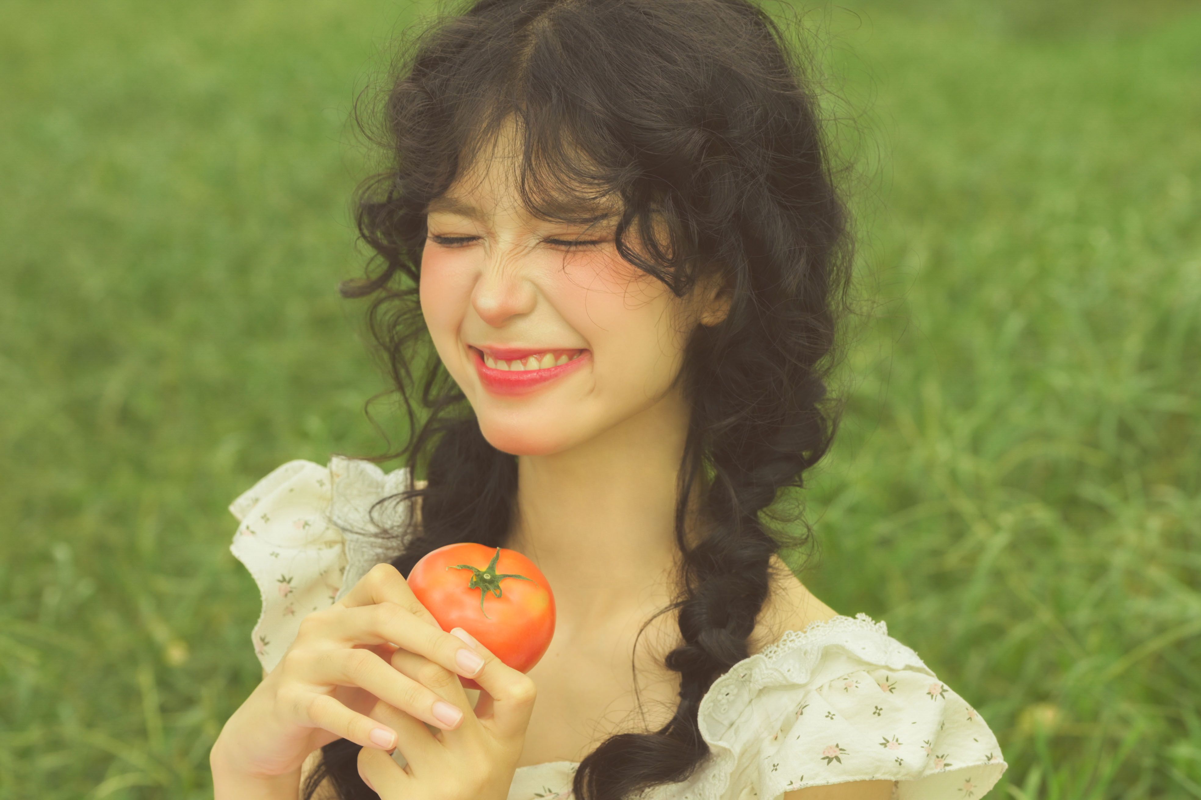 Young Woman Joyfully Holding a Fresh Tomato · Free Stock Photo