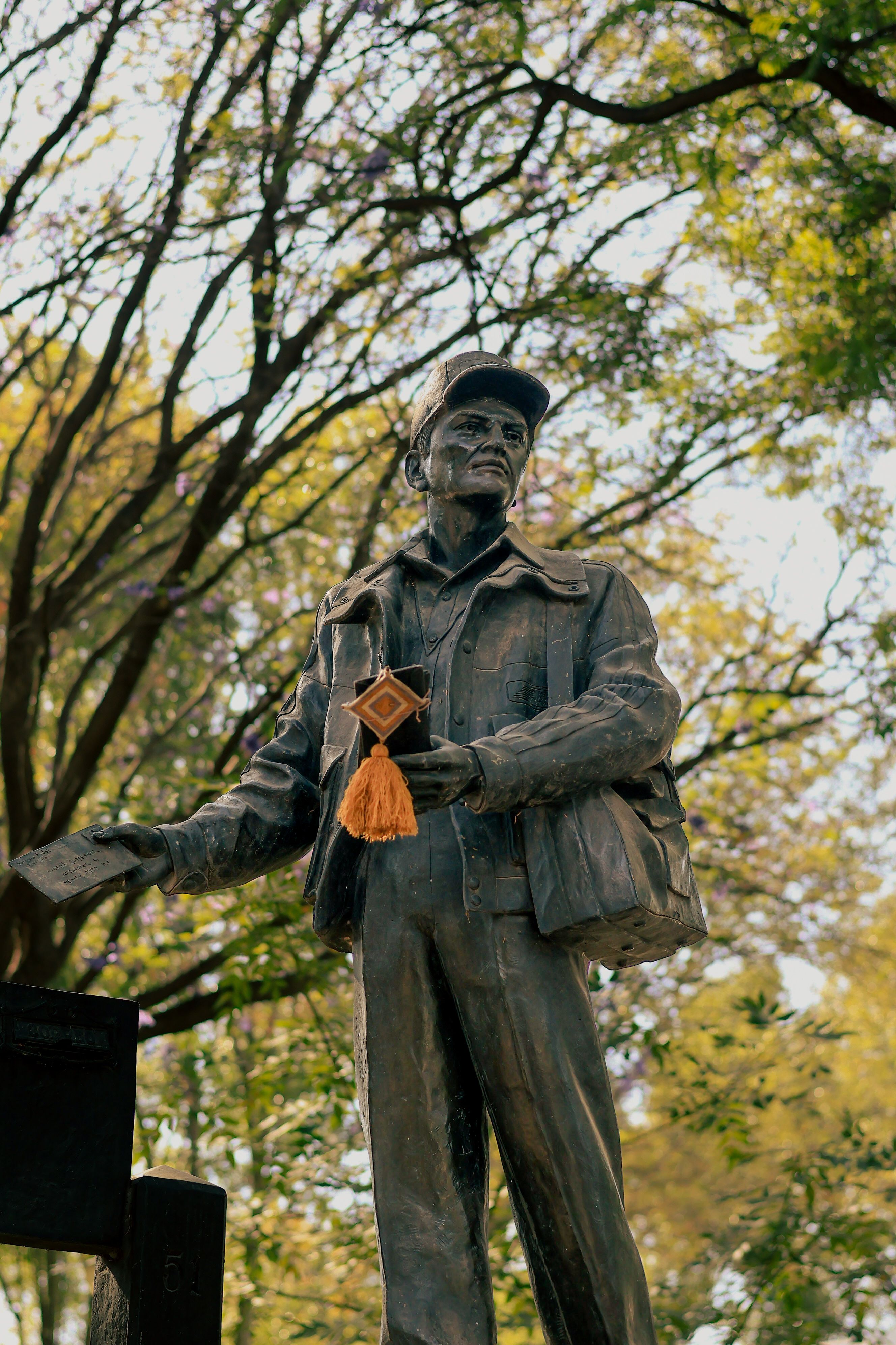 Bronze Statue of Mailman Under Trees · Free Stock Photo