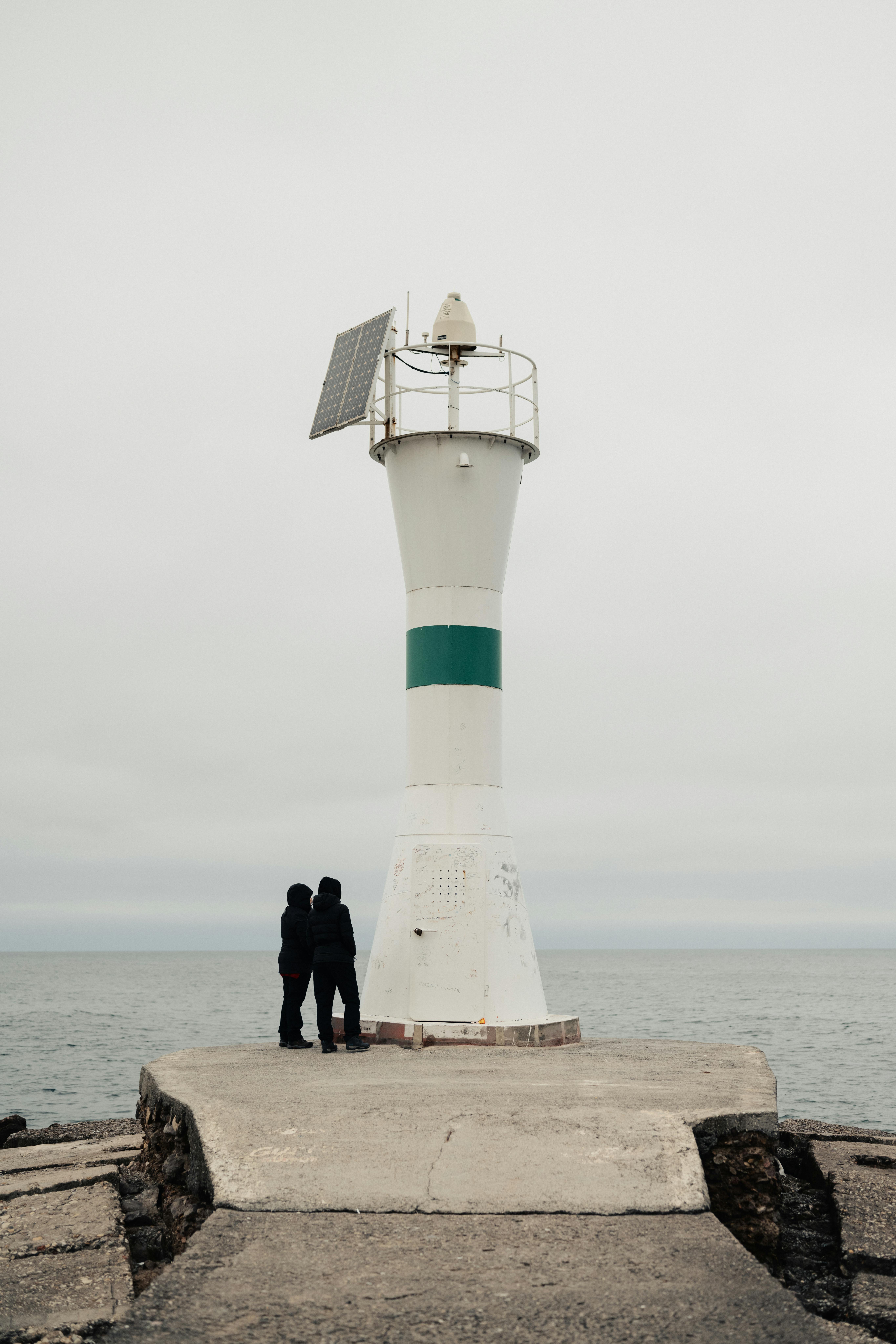 Dramatic Lighthouse Scene with Silhouetted Figures · Free Stock Photo