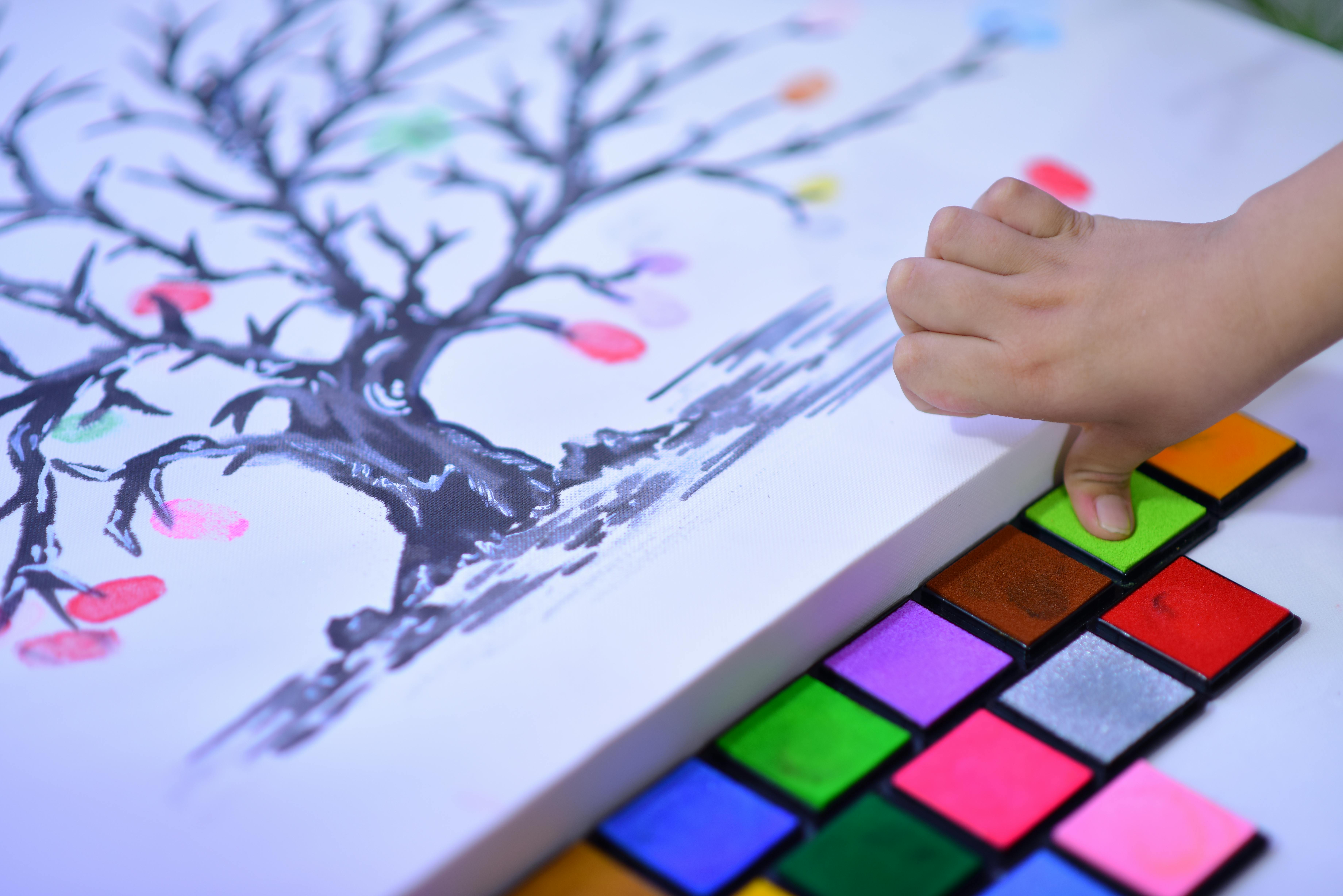 Child Adding Fingerprints to Colorful Tree Painting · Free Stock Photo