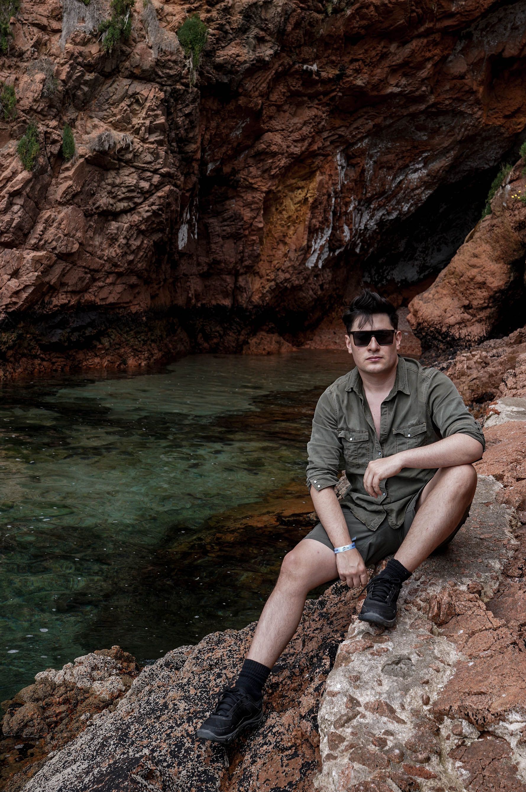 Man Relaxing by Rocky Coastal Cave · Free Stock Photo