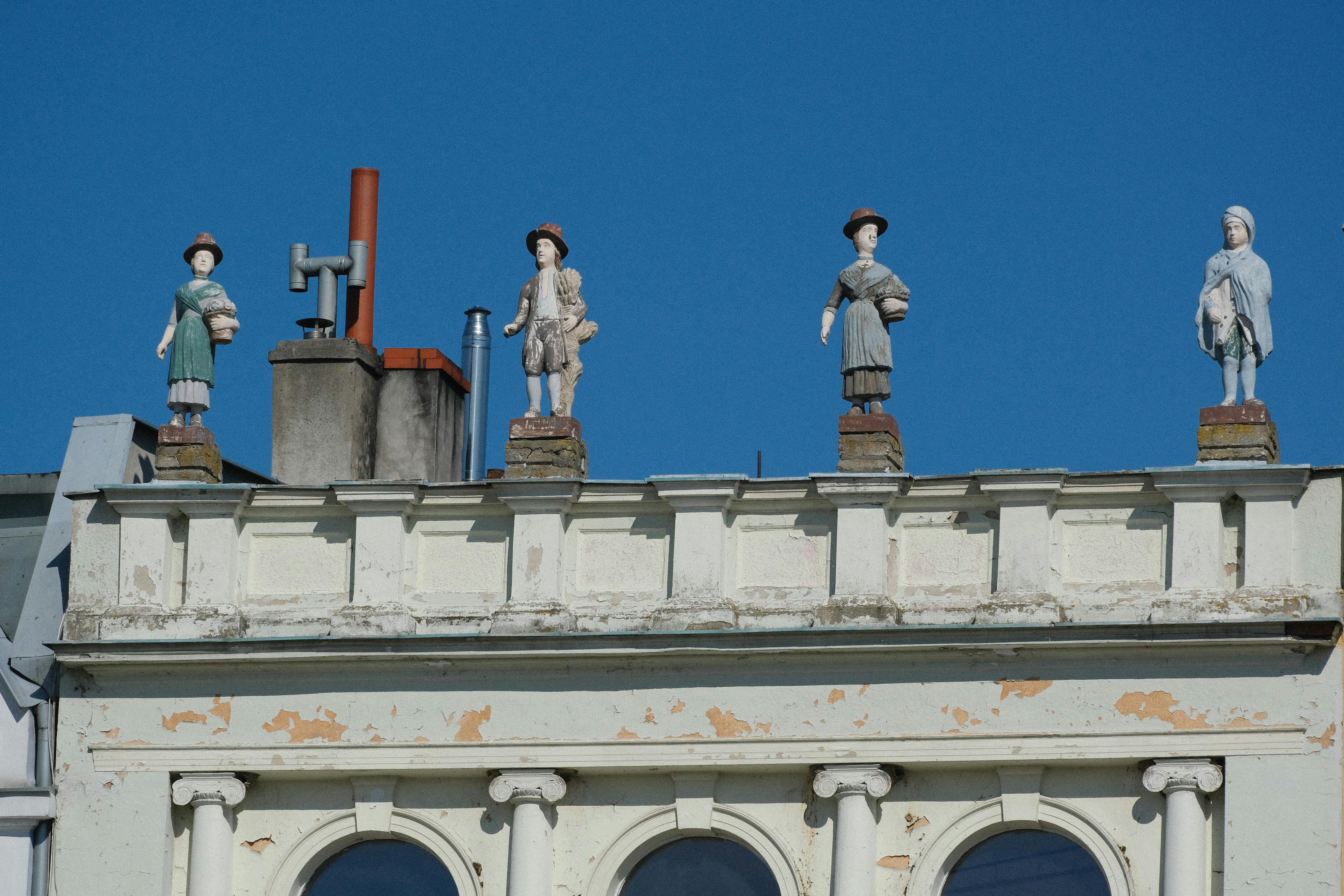 Charming Rooftop Statues Under Clear Blue Sky · Free Stock Photo