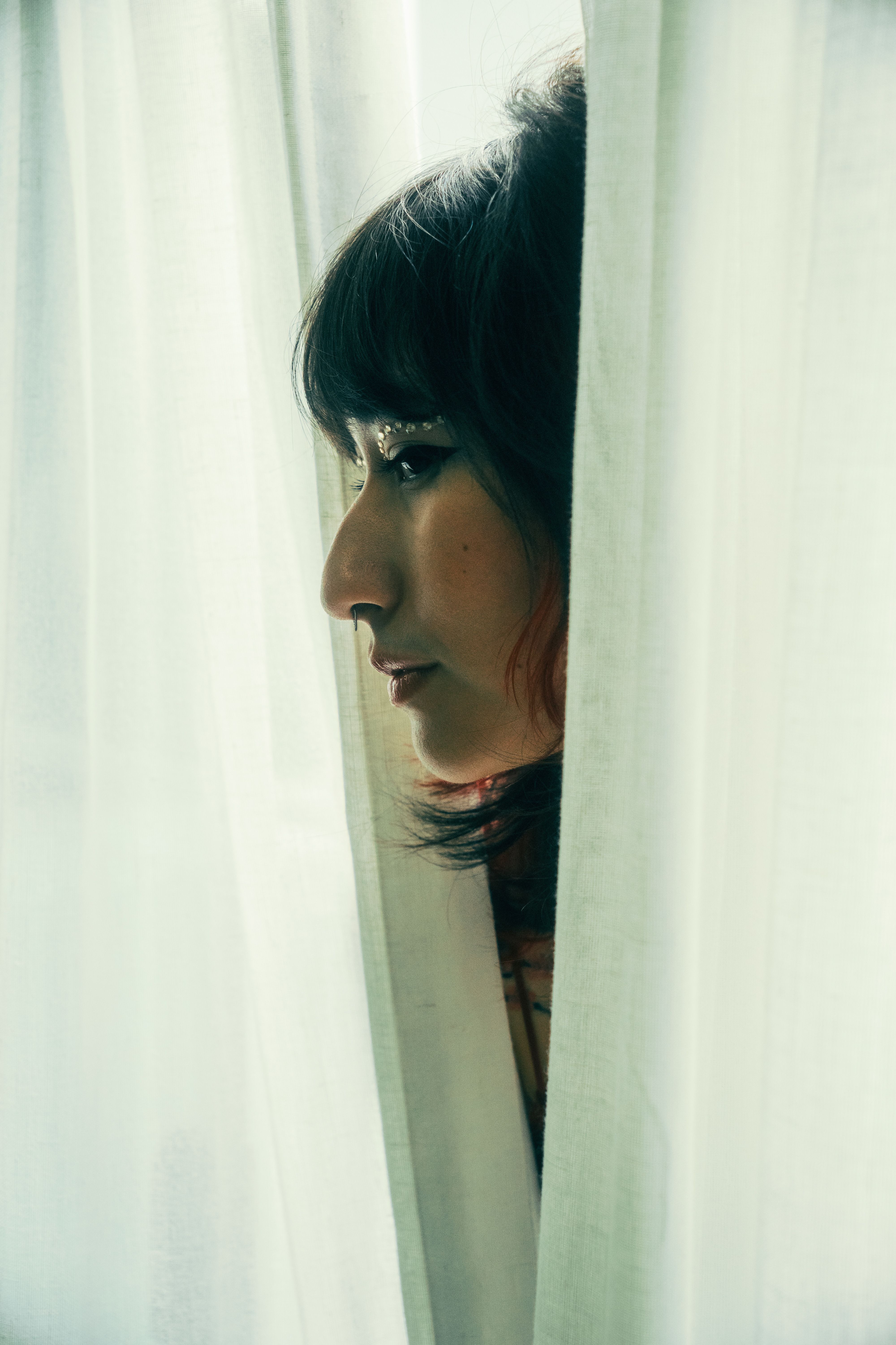 Pensive Woman Gazing Through White Curtains · Free Stock Photo