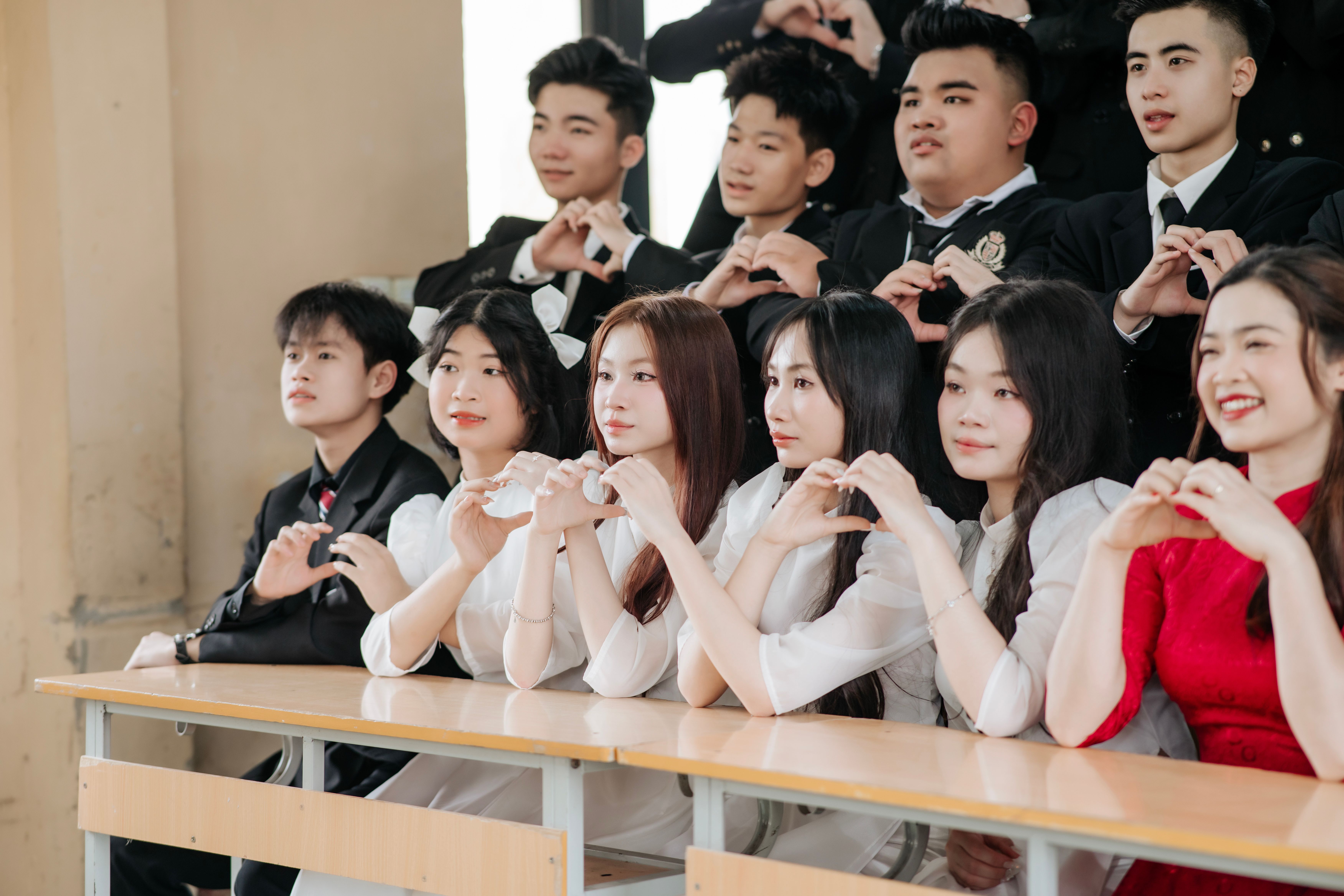 Group of Students in Classroom Making Heart Shapes · Free Stock Photo
