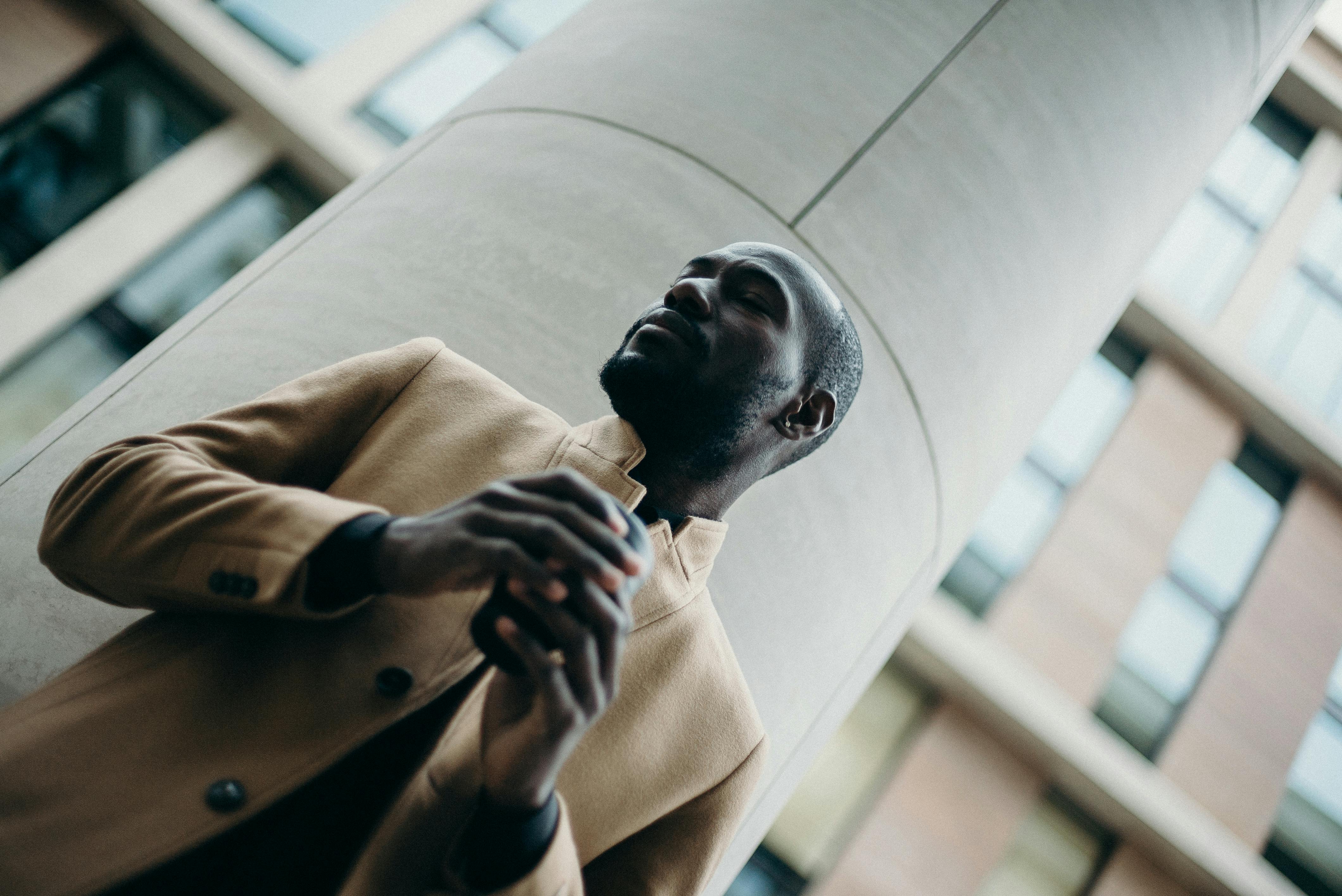 Low Angle Photo of Man in Brown Coat Standing Beside White Column ...