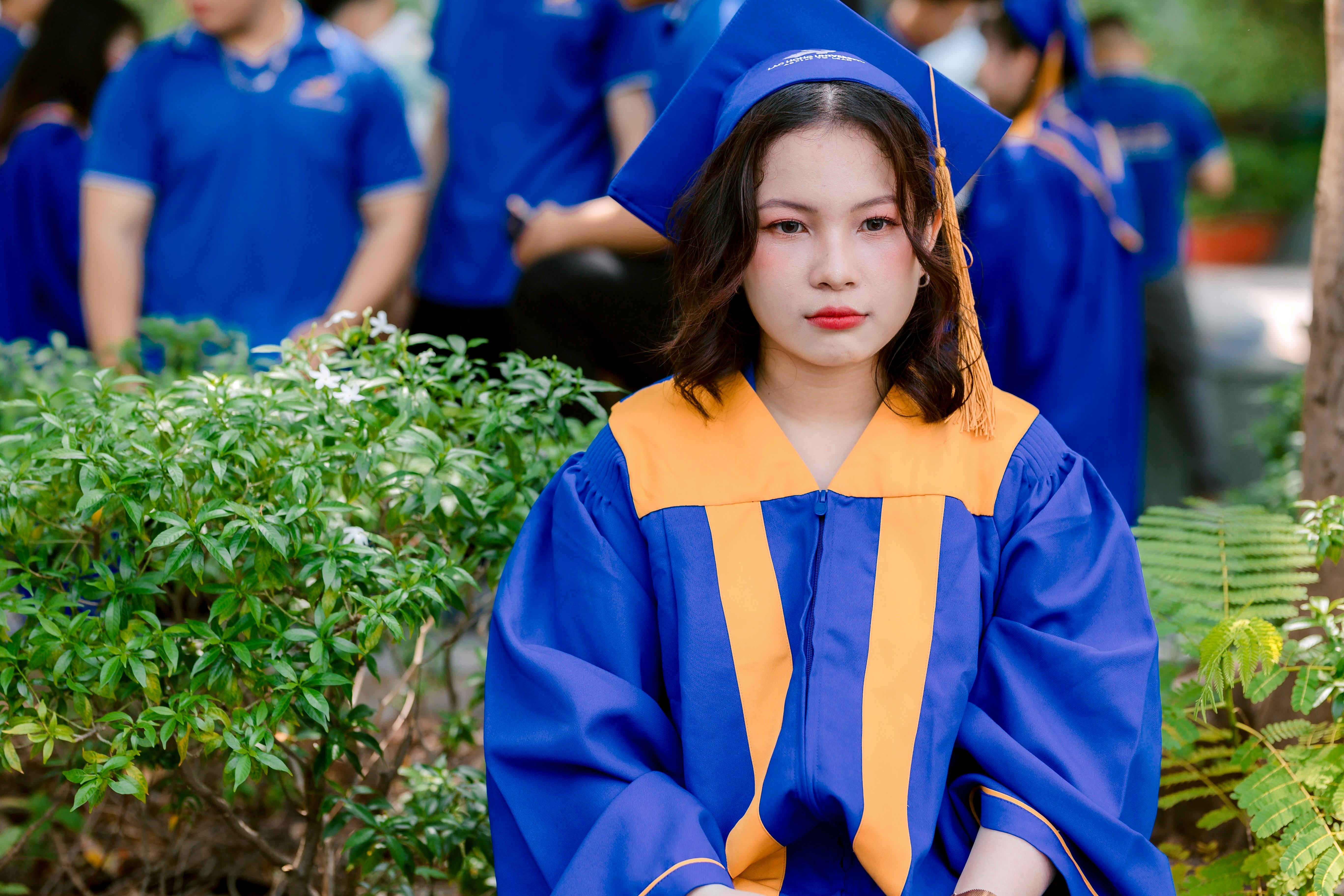 Young Graduate in Blue Gown at Outdoor Ceremony · Free Stock Photo