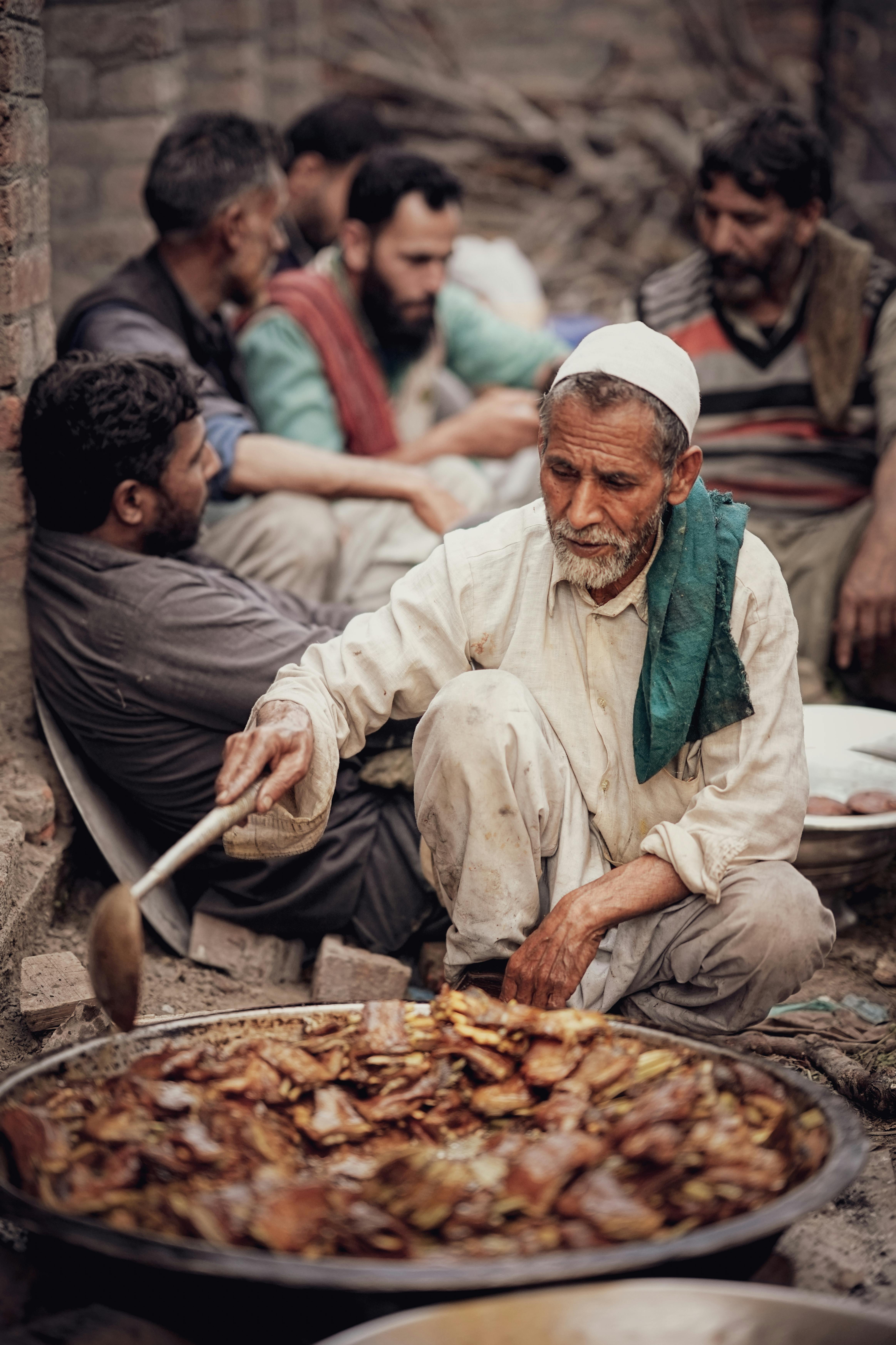 Elderly Man Cooking Traditional Dish Outdoors · Free Stock Photo