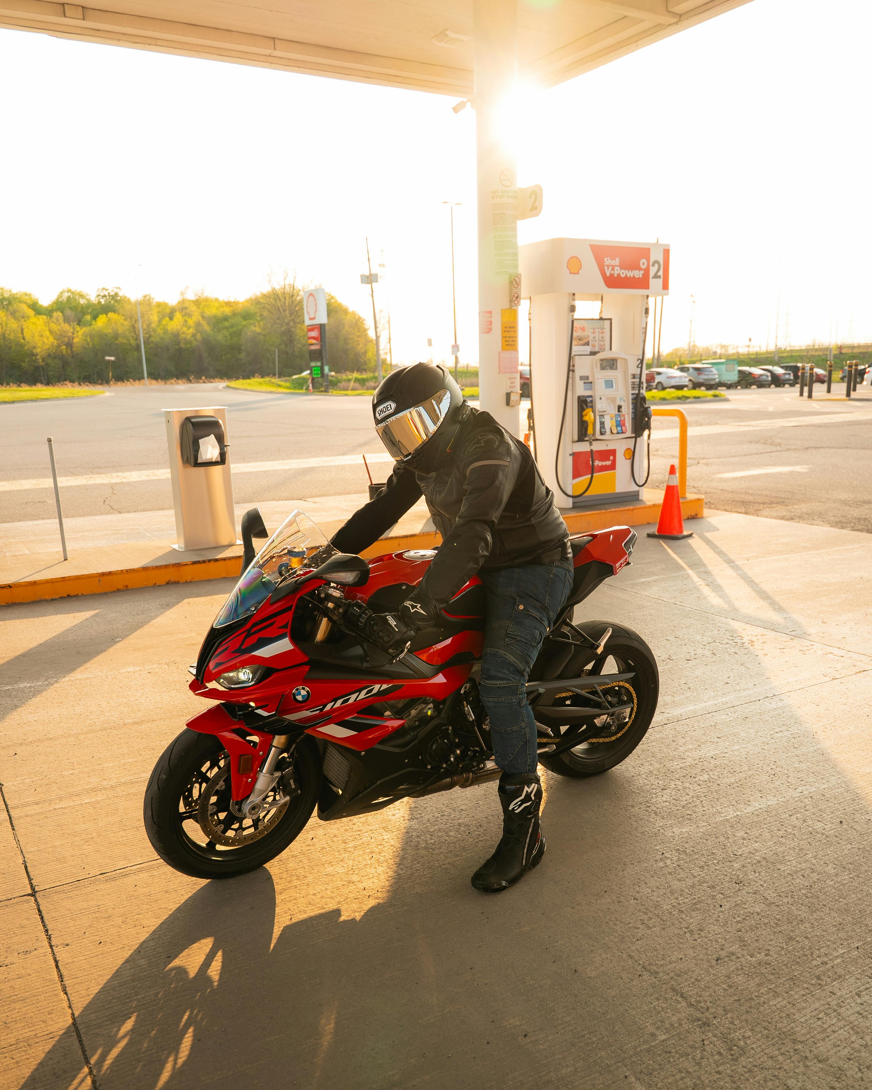 Motorcyclist Refueling at Sunlit Gas Station · Free Stock Photo