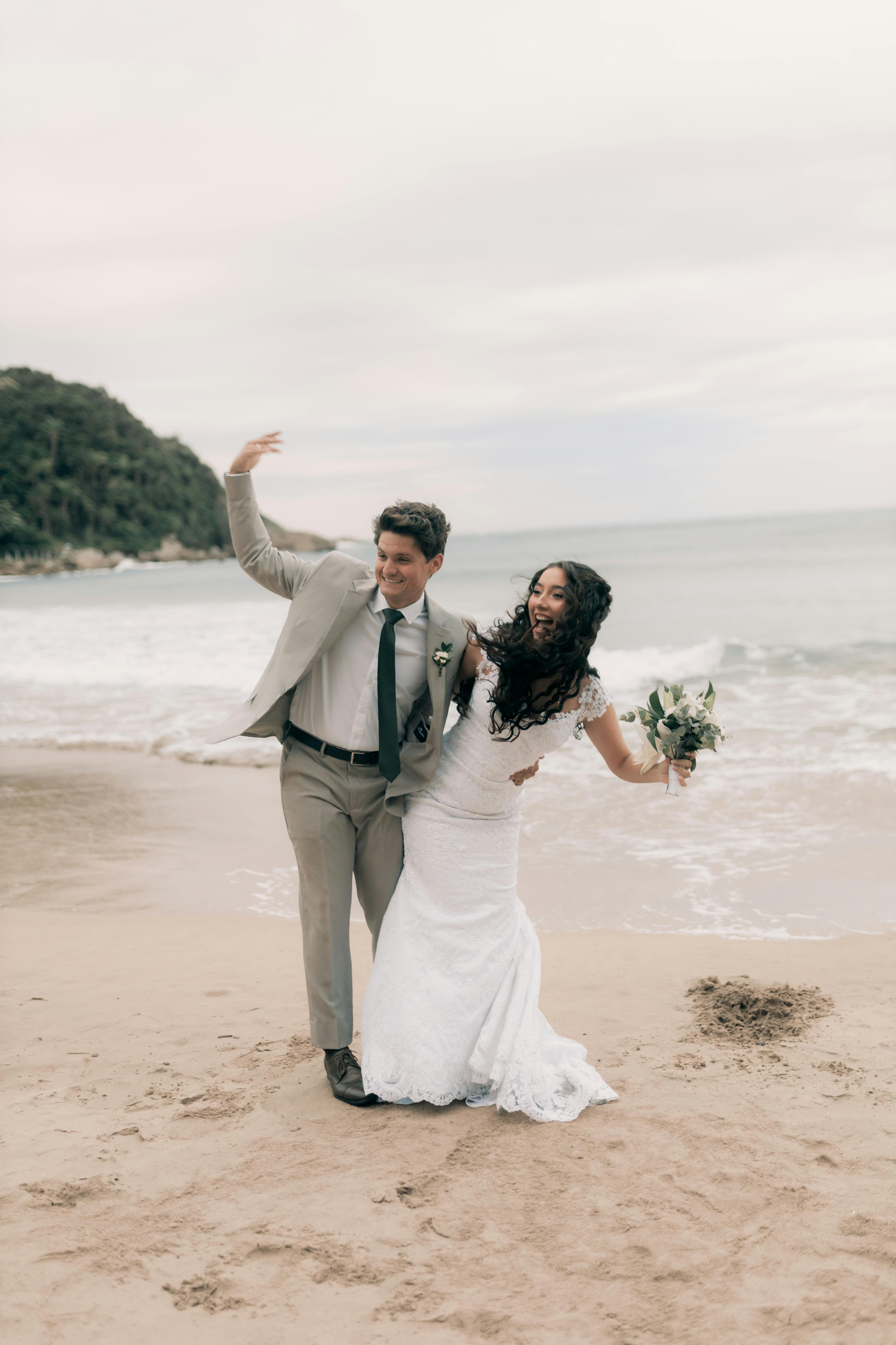 Joyful Beach Wedding Couple Embracing by the Waves · Free Stock Photo