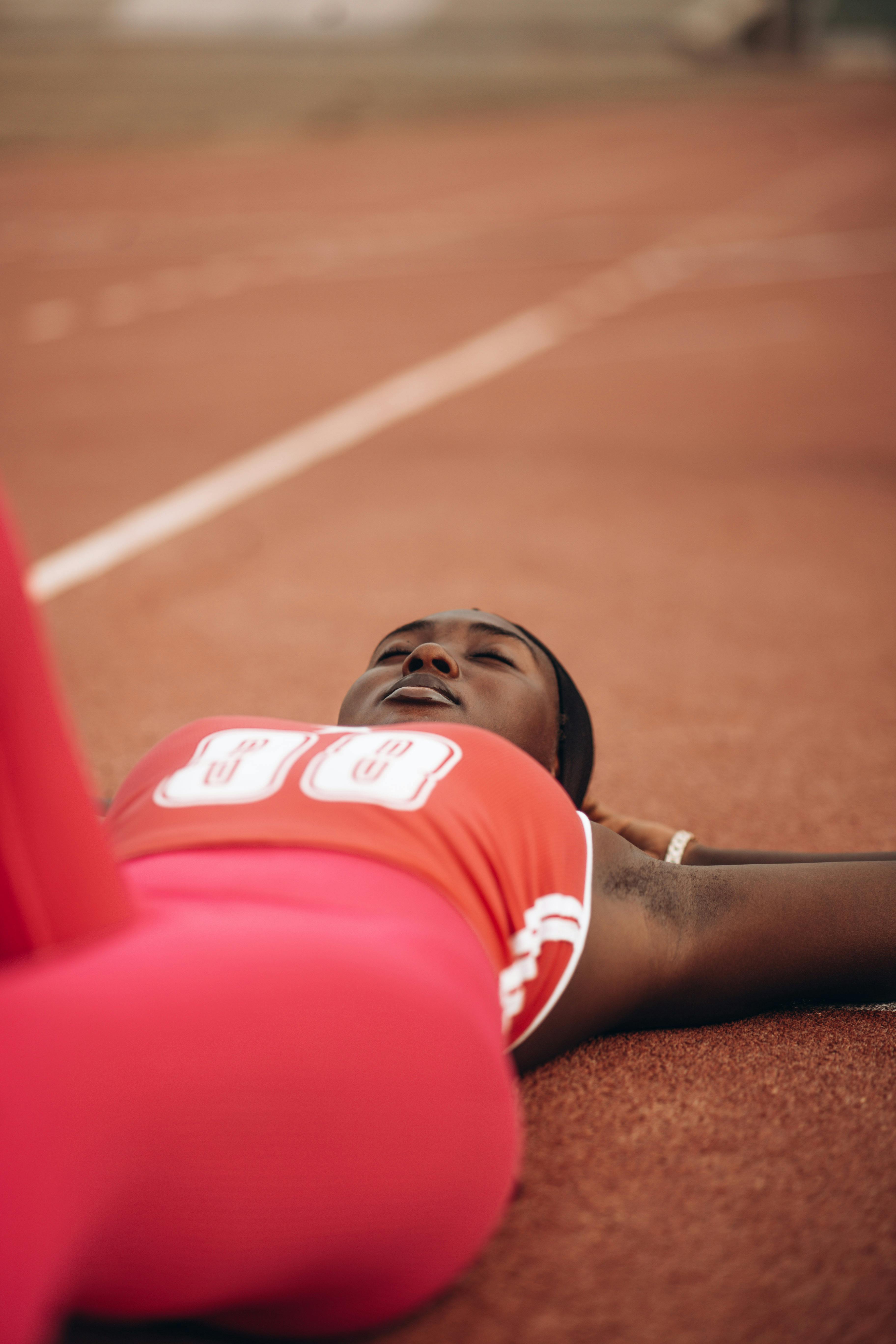 Athlete Resting on Track in Red Sportswear · Free Stock Photo