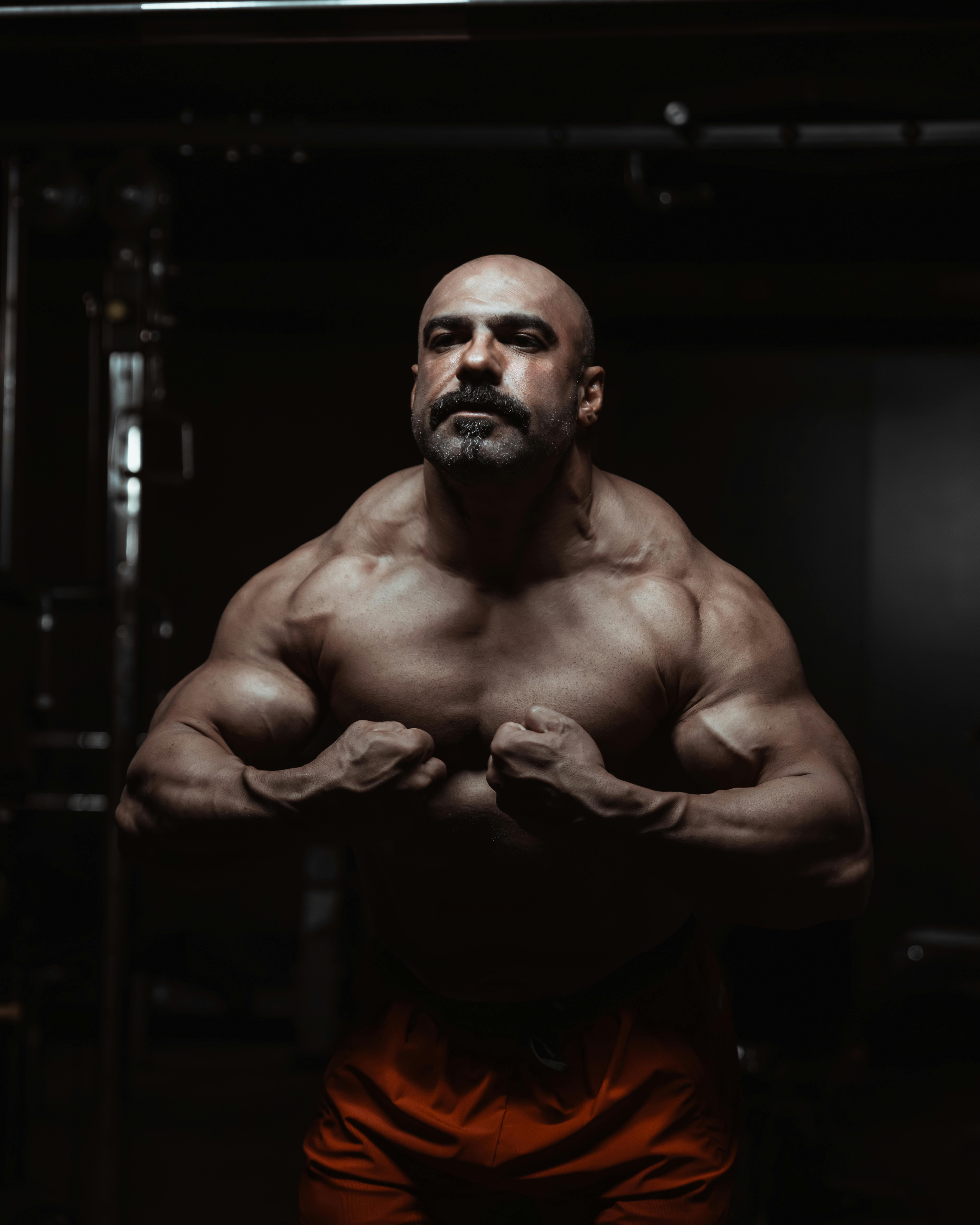 Powerful Bodybuilder Posing in Dark Gym · Free Stock Photo