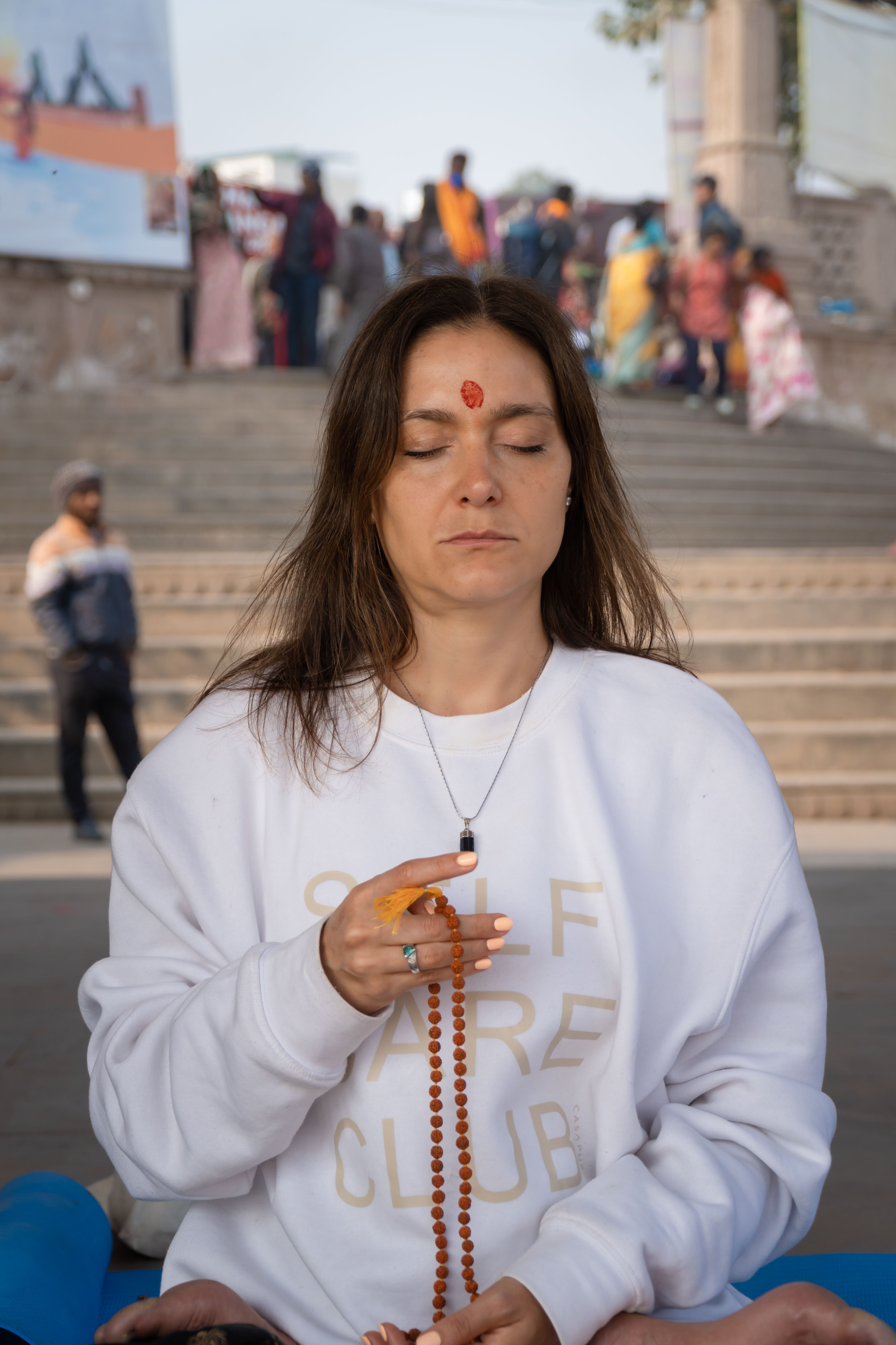 Woman Meditating with Mala Beads in Indian Street · Free Stock Photo