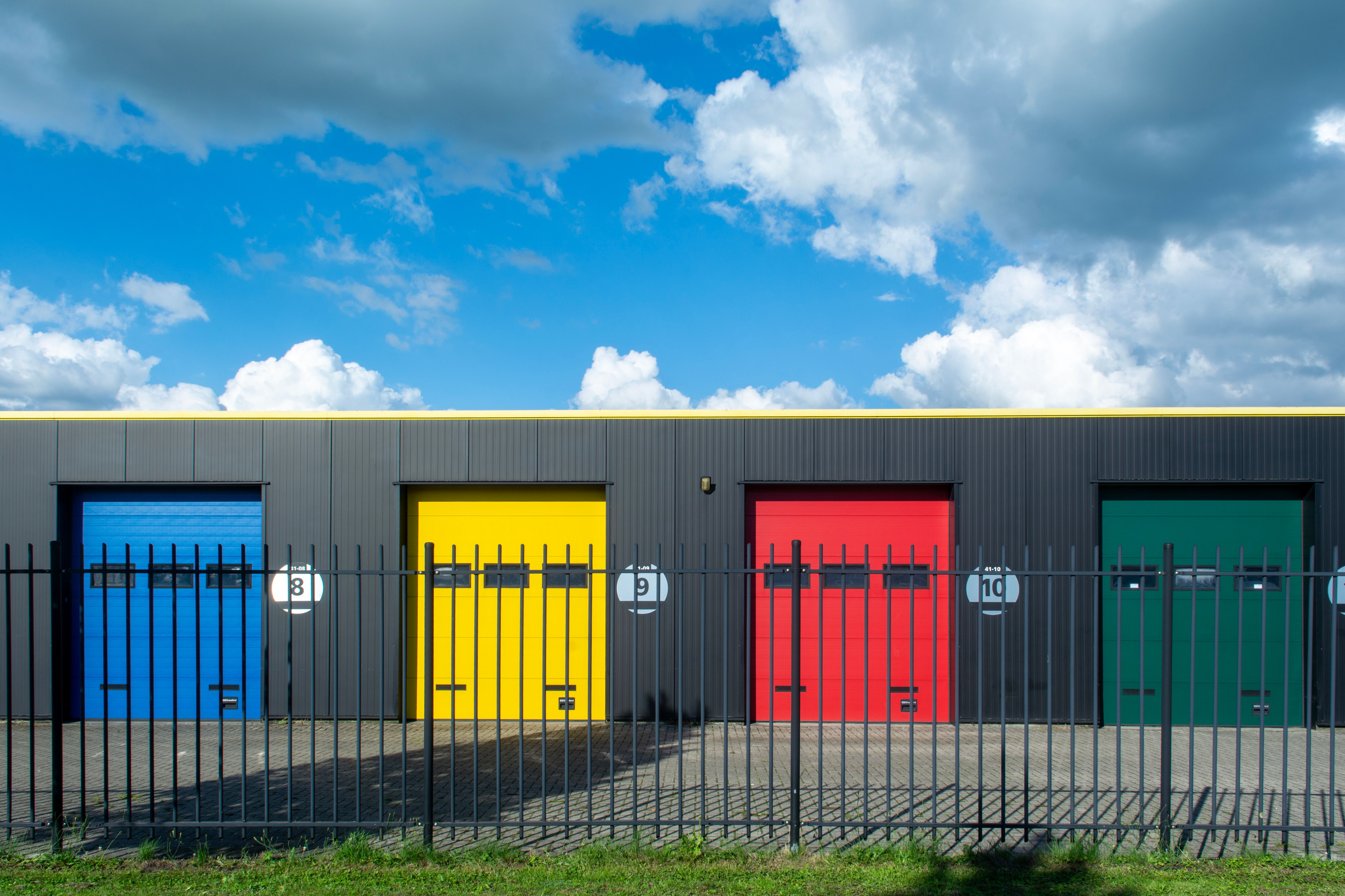 Colorful Industrial Garage Doors Against Blue Sky · Free Stock Photo