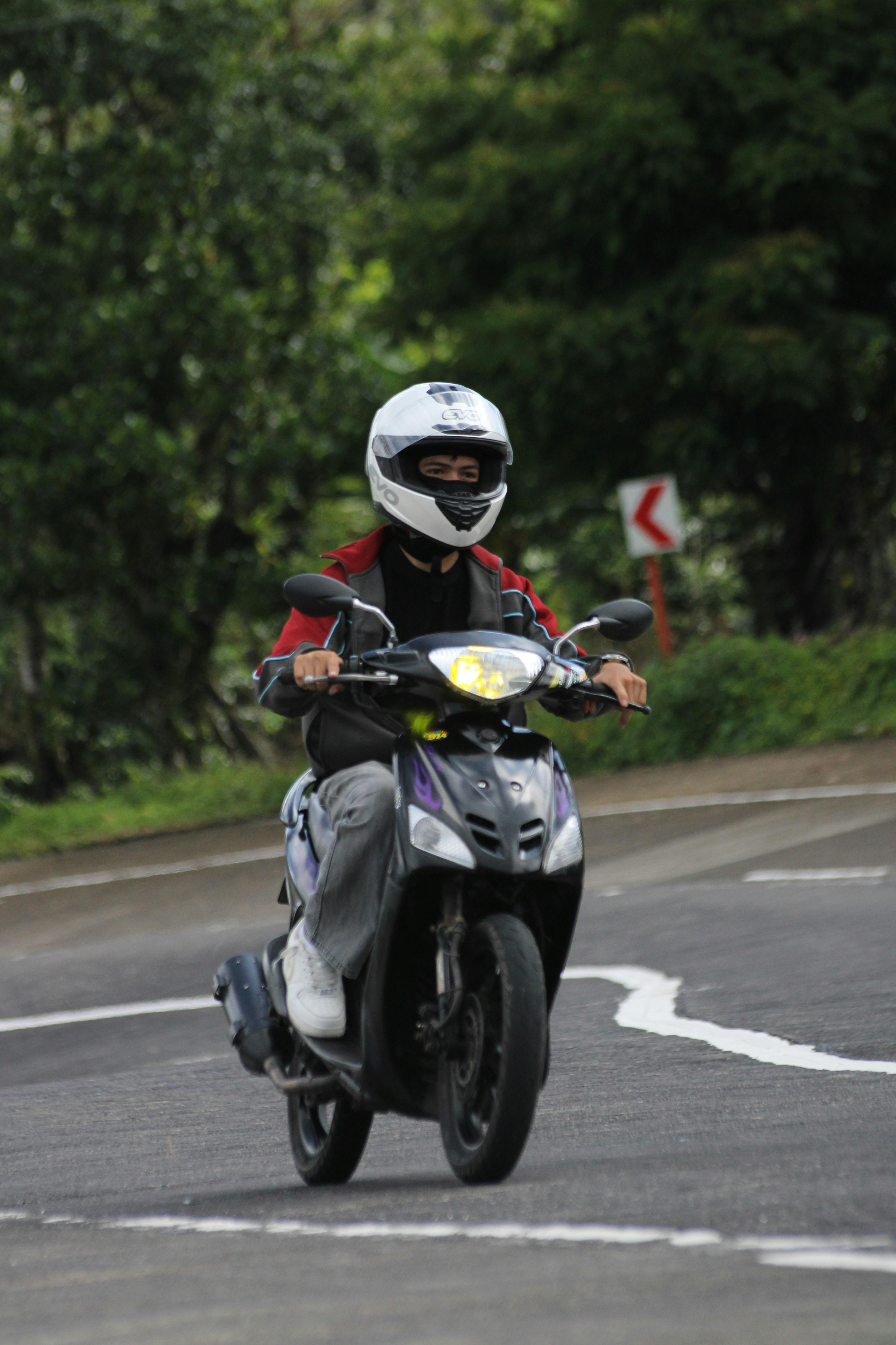 Person Riding Scooter on Curved Road Outdoors · Free Stock Photo