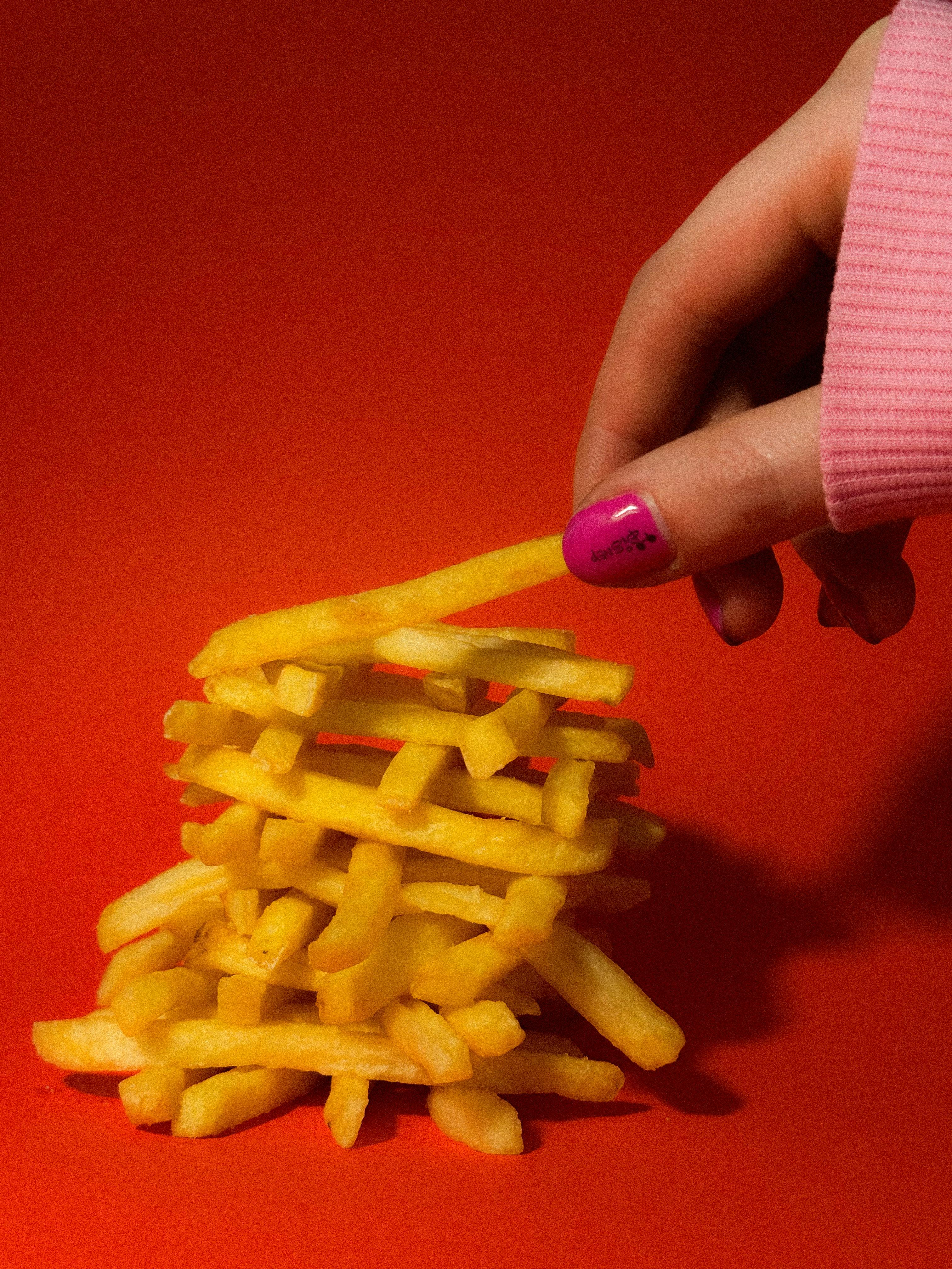 Stack of French Fries Against Bold Red Background · Free Stock Photo