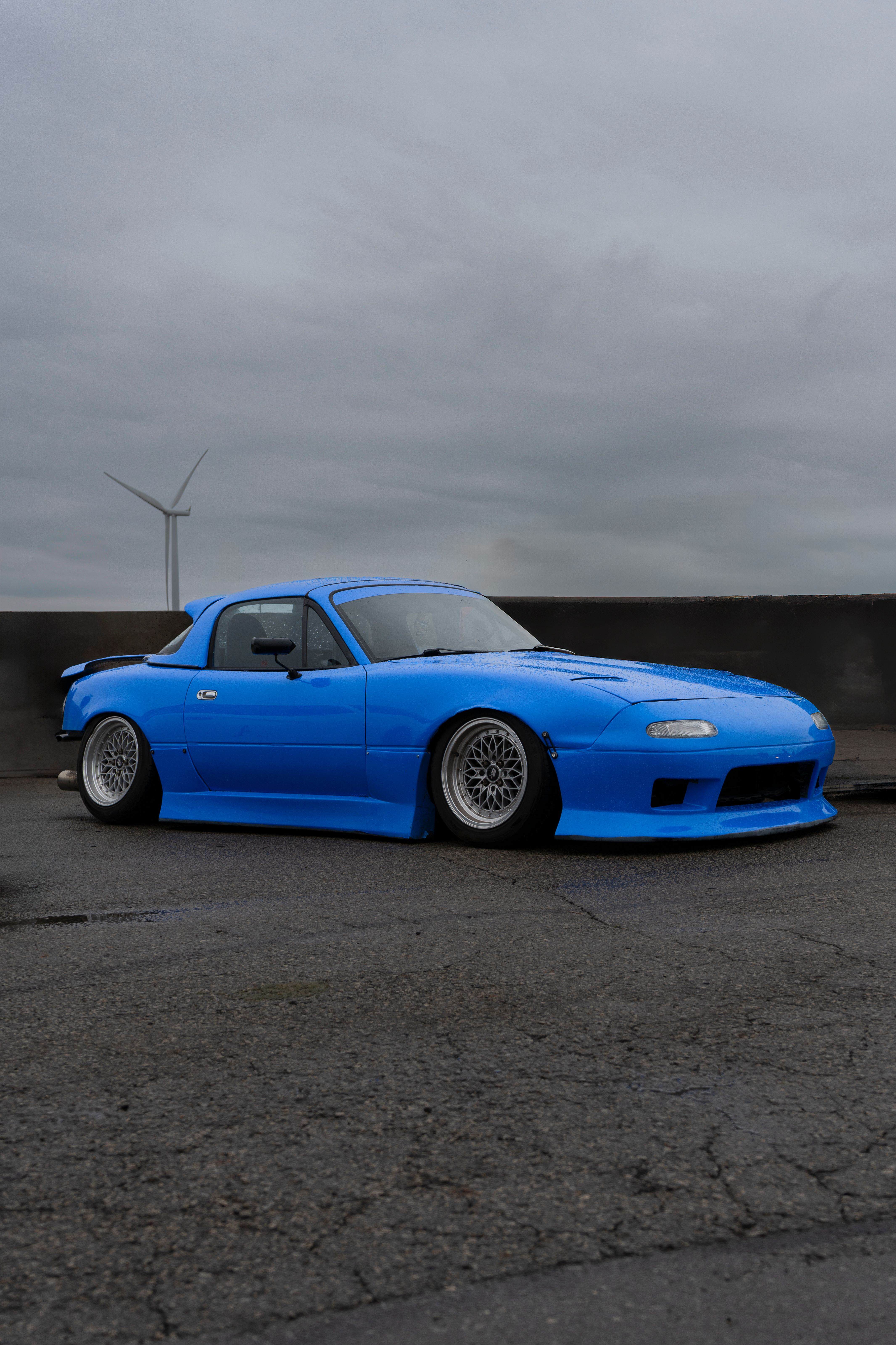 Blue Modified Car on Urban Asphalt with Wind Turbine · Free Stock Photo