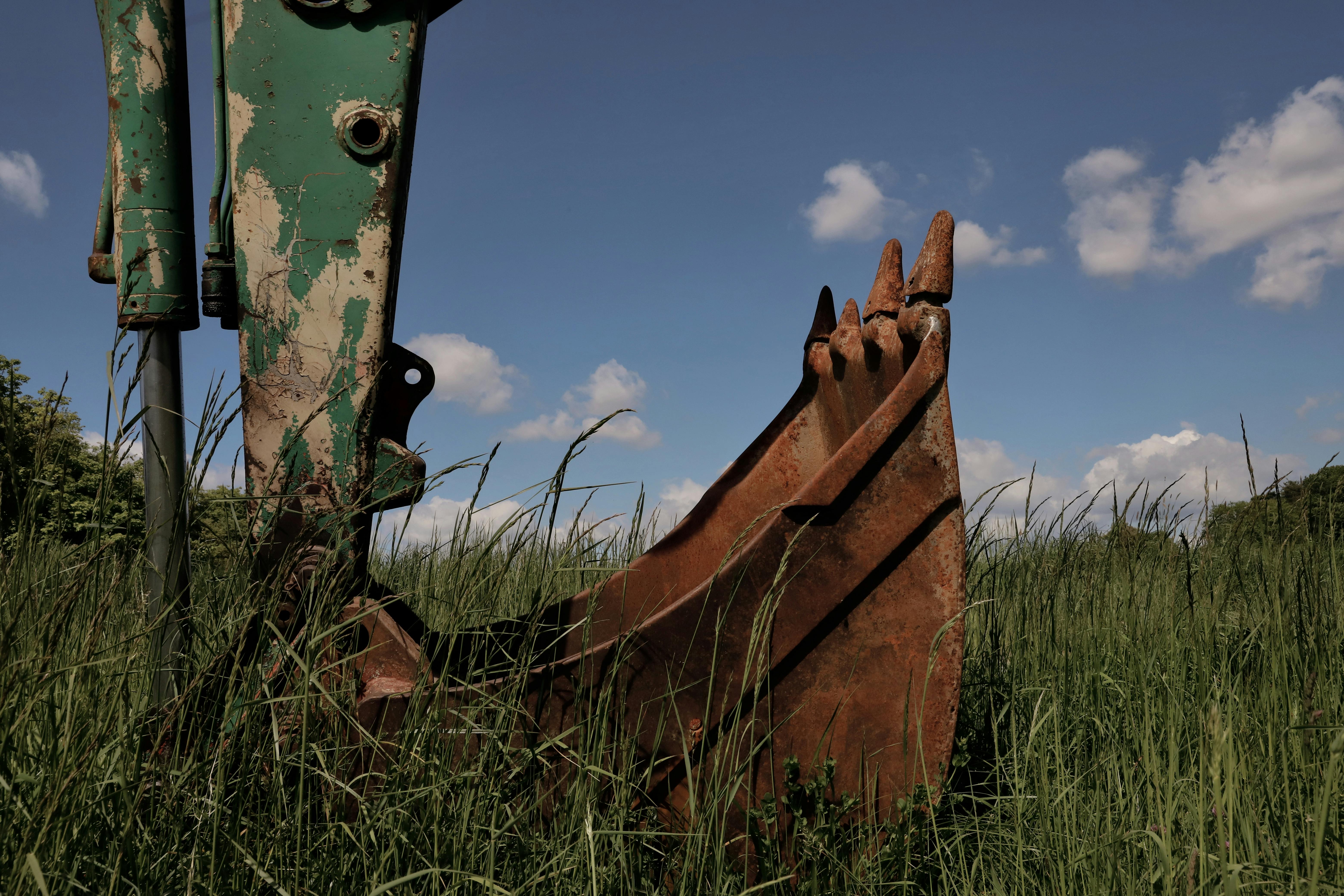 Rusty Excavator Bucket in Overgrown Field · Free Stock Photo