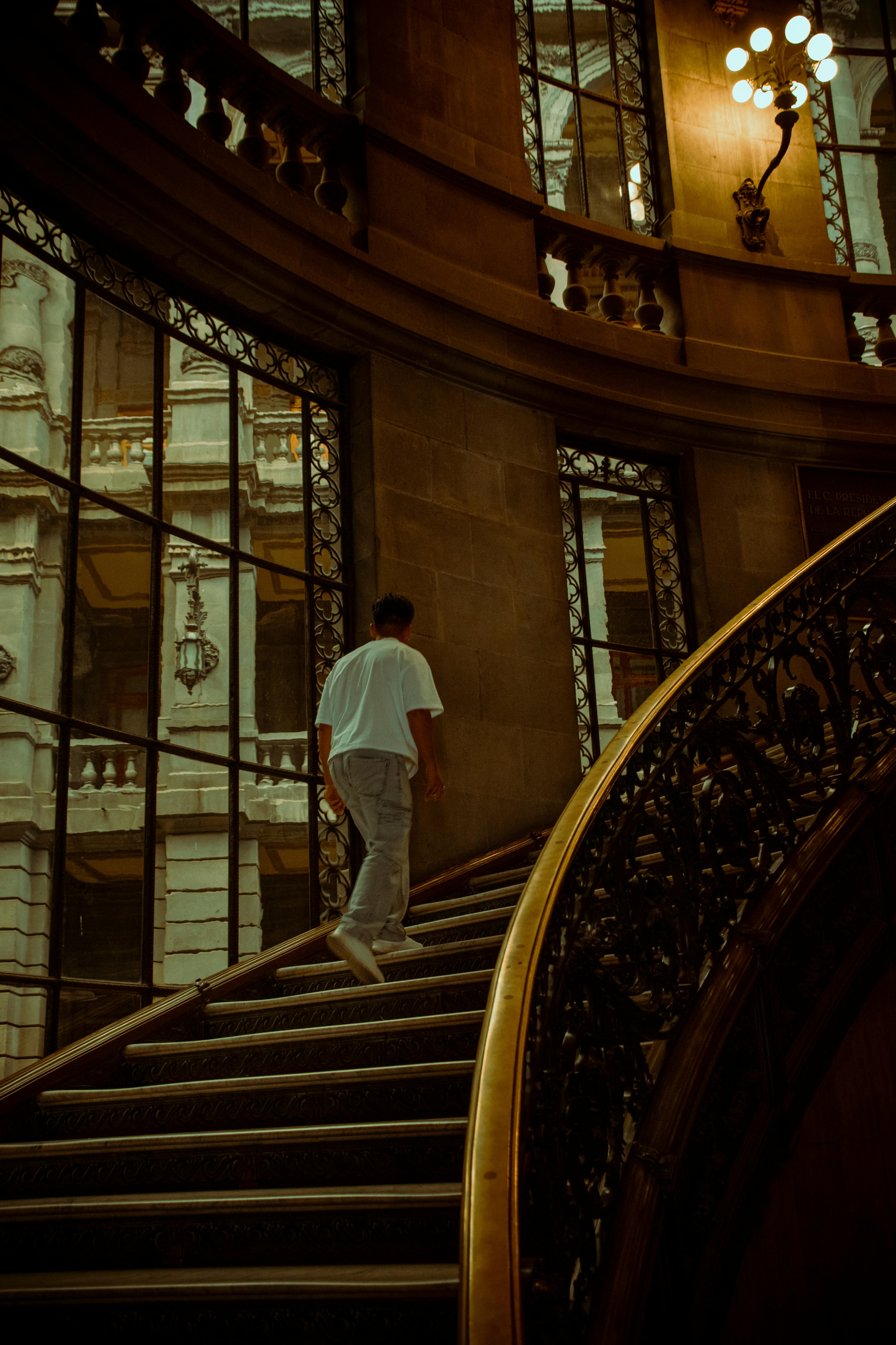 Man Climbing Elegant Curved Staircase Indoors · Free Stock Photo