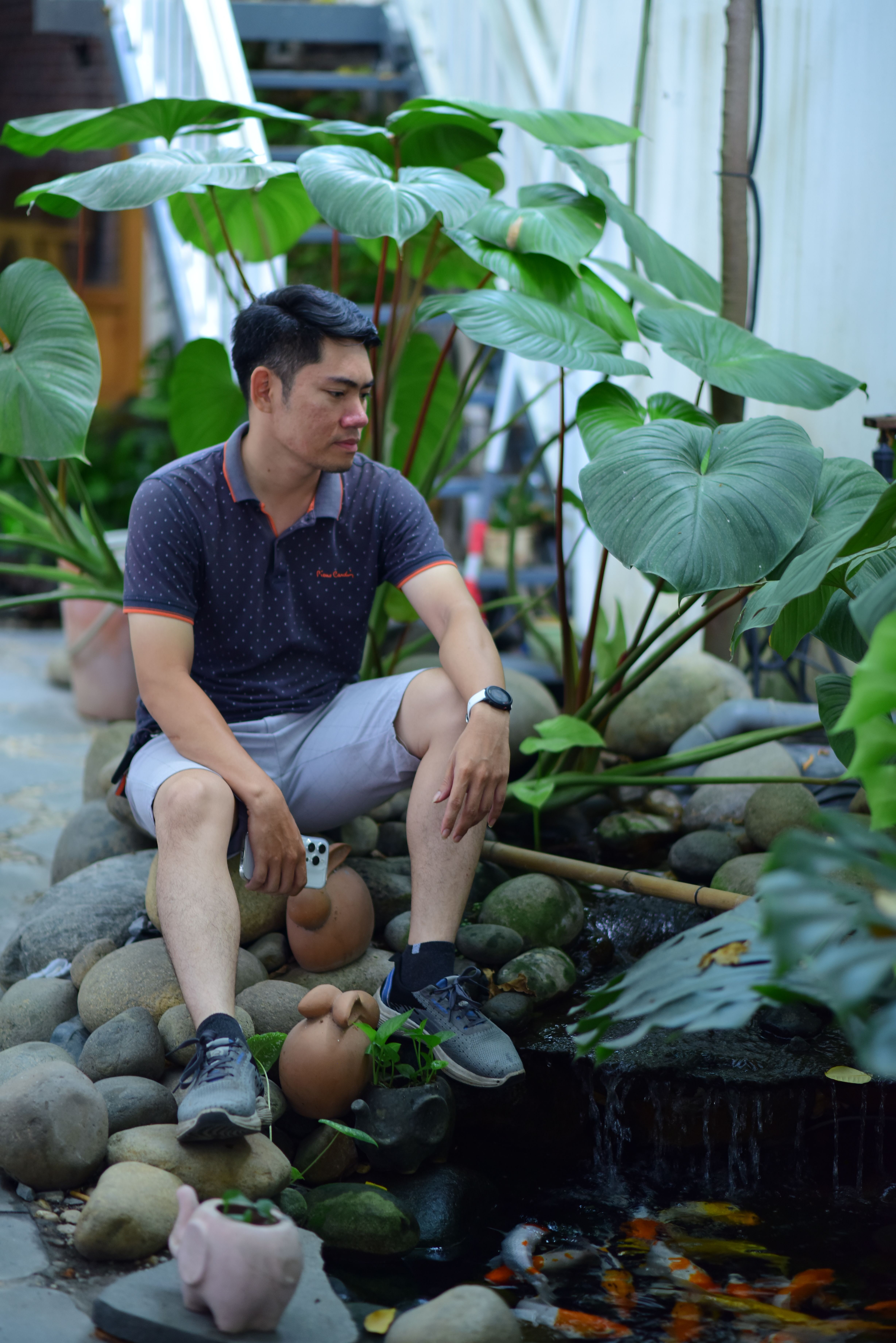 Man Relaxing by Indoor Pond with Lush Greenery · Free Stock Photo