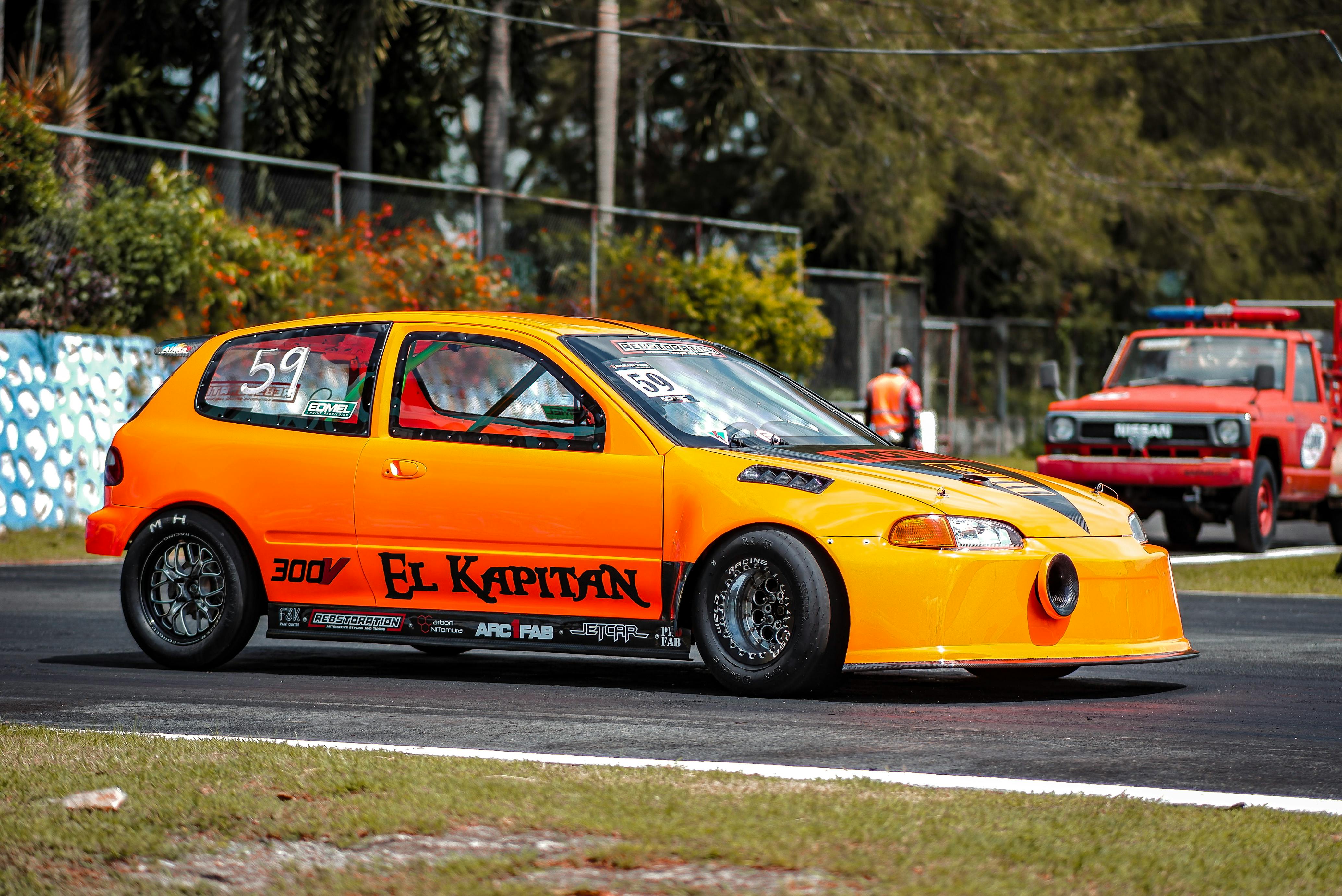 High-Speed Orange Racing Car on Track · Free Stock Photo