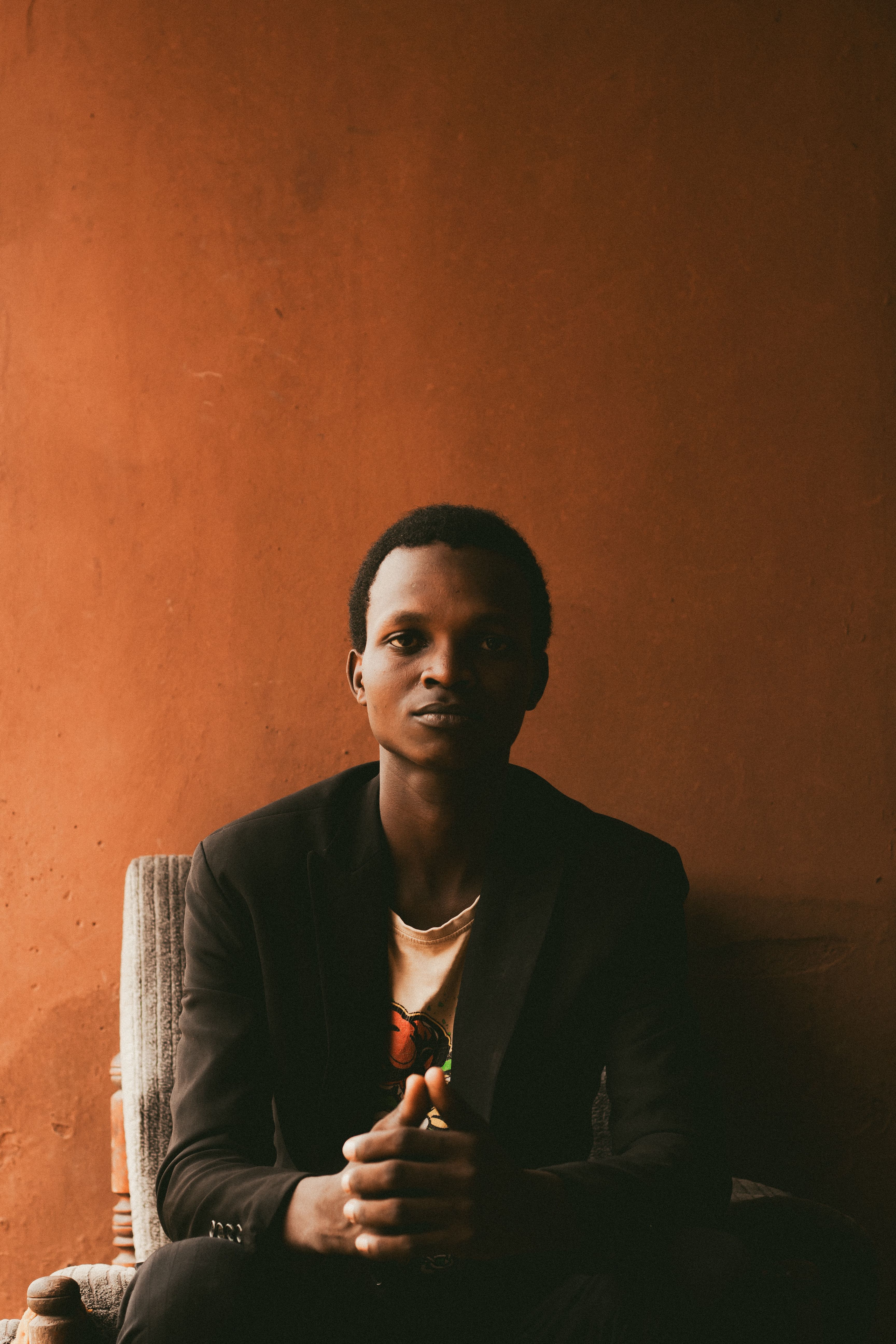 Portrait of a Man Seated Against Brown Wall · Free Stock Photo