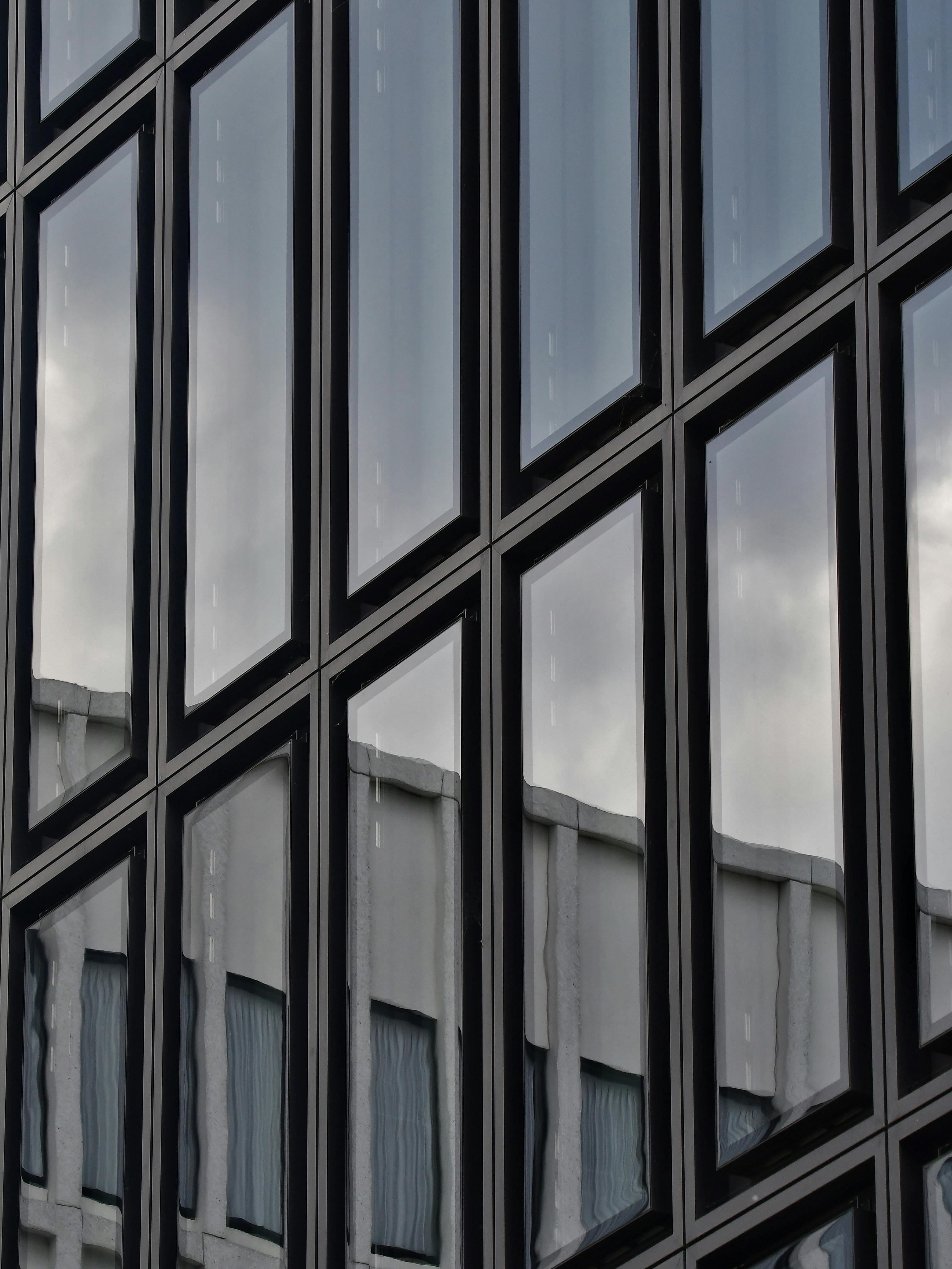 Modern Glass Facade Reflecting Urban Skies · Free Stock Photo
