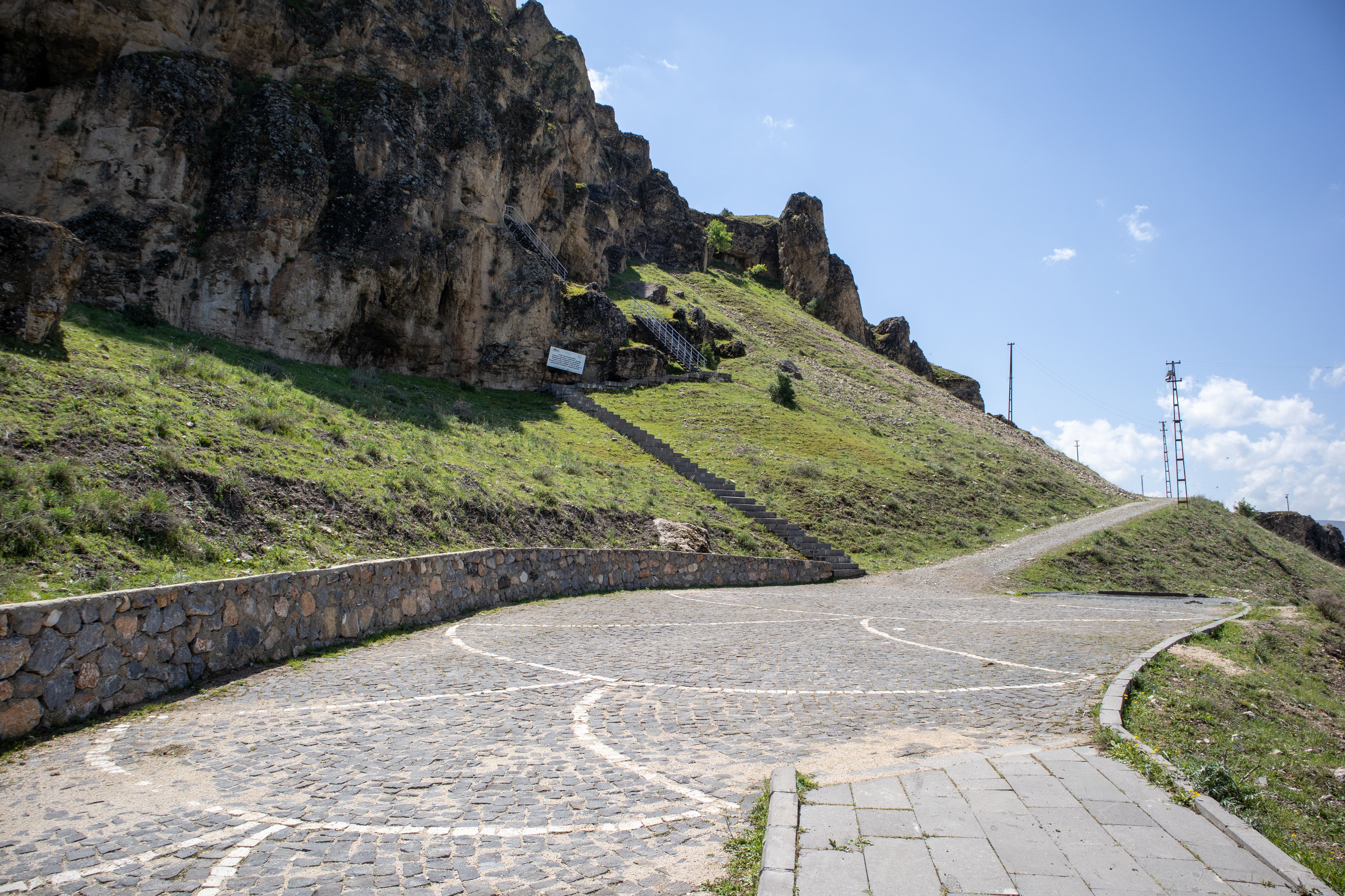 Cobblestone Pathway Beneath Rocky Cliff · Free Stock Photo