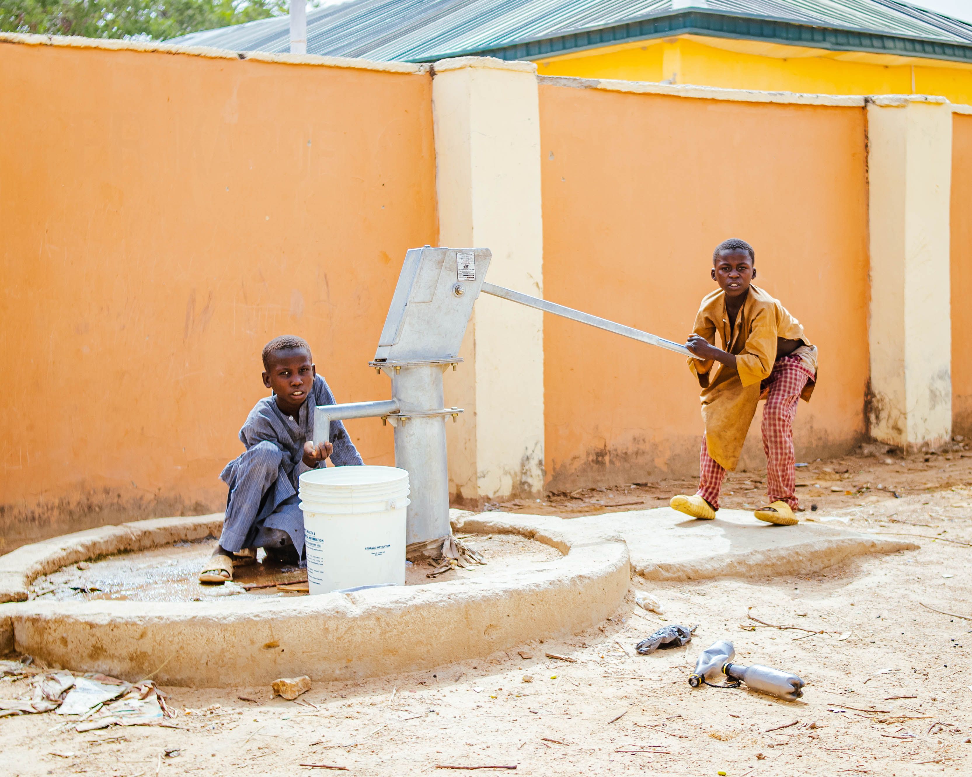 Children Pumping Water at Outdoor Well · Free Stock Photo