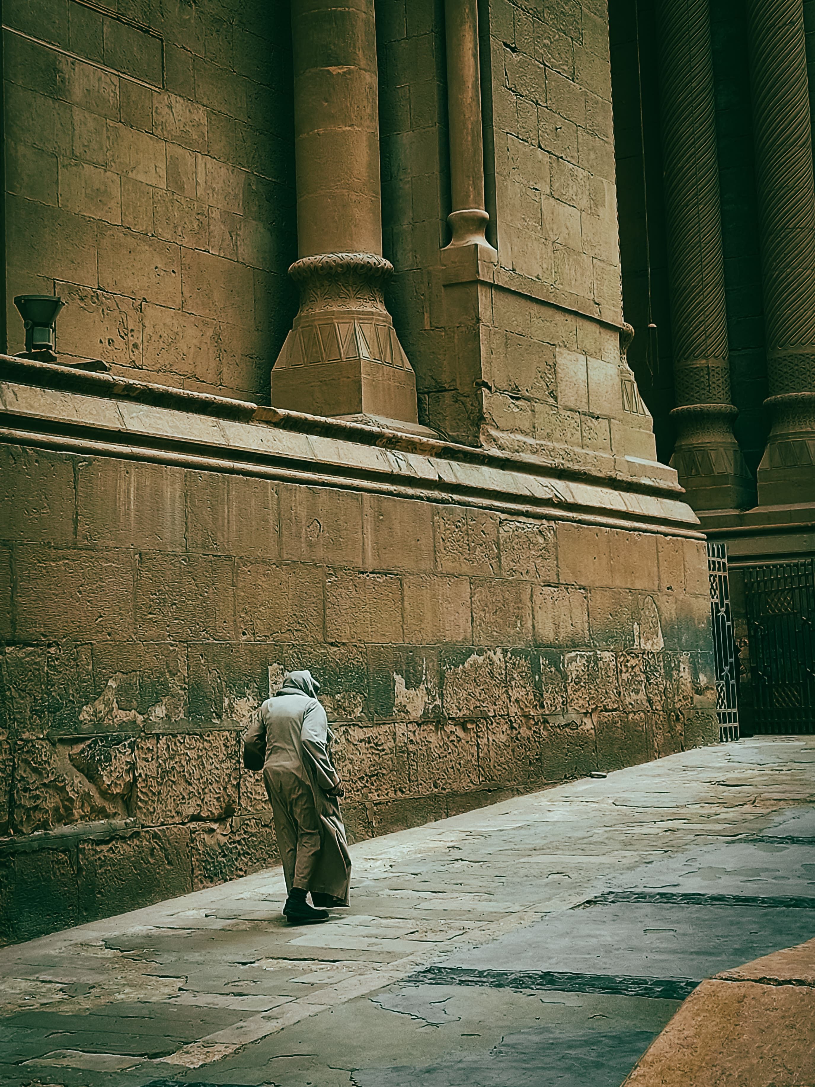 Elderly Person Walking Beside Ancient Stone Wall · Free Stock Photo