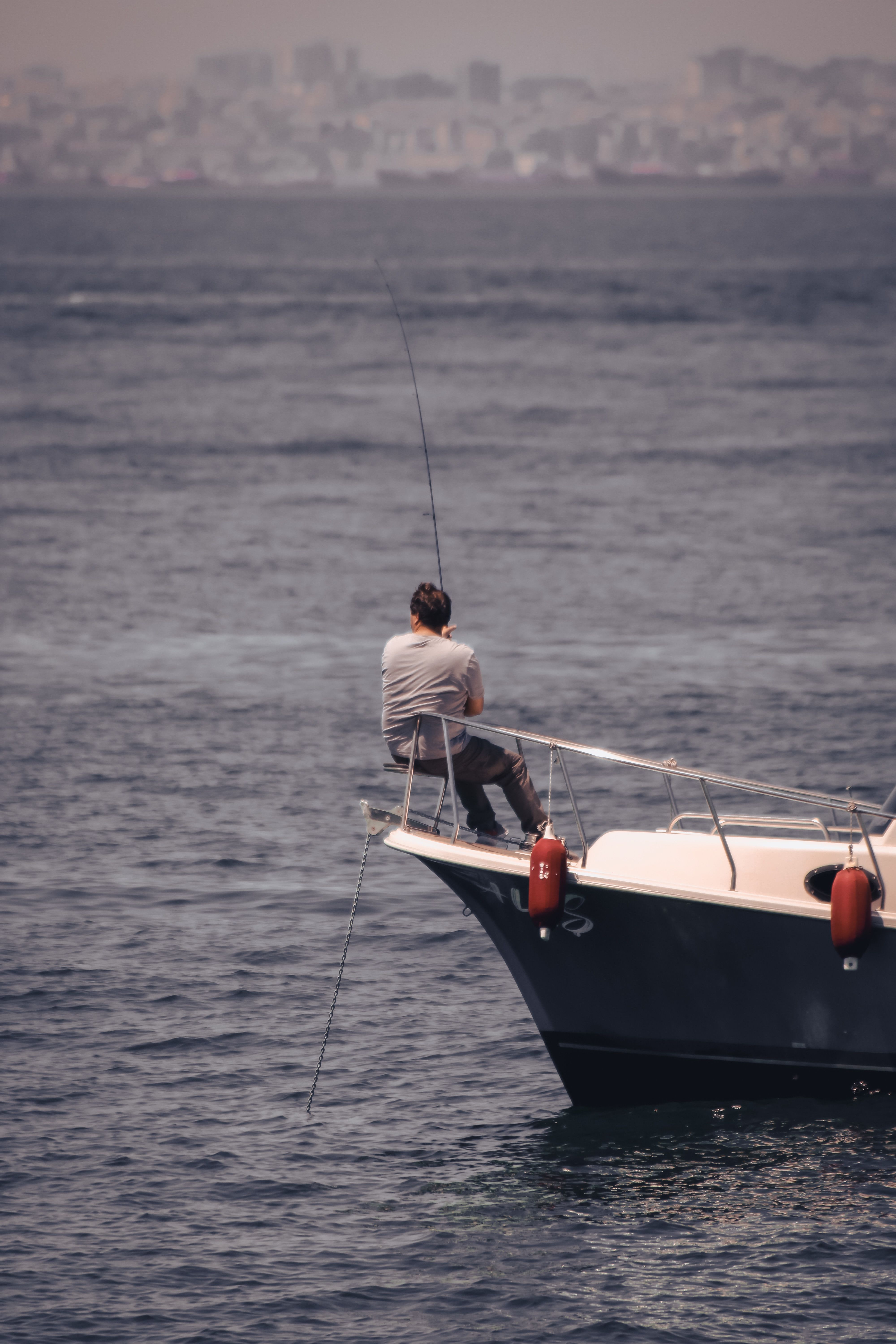 Man Fishing on Boat with City Skyline · Free Stock Photo