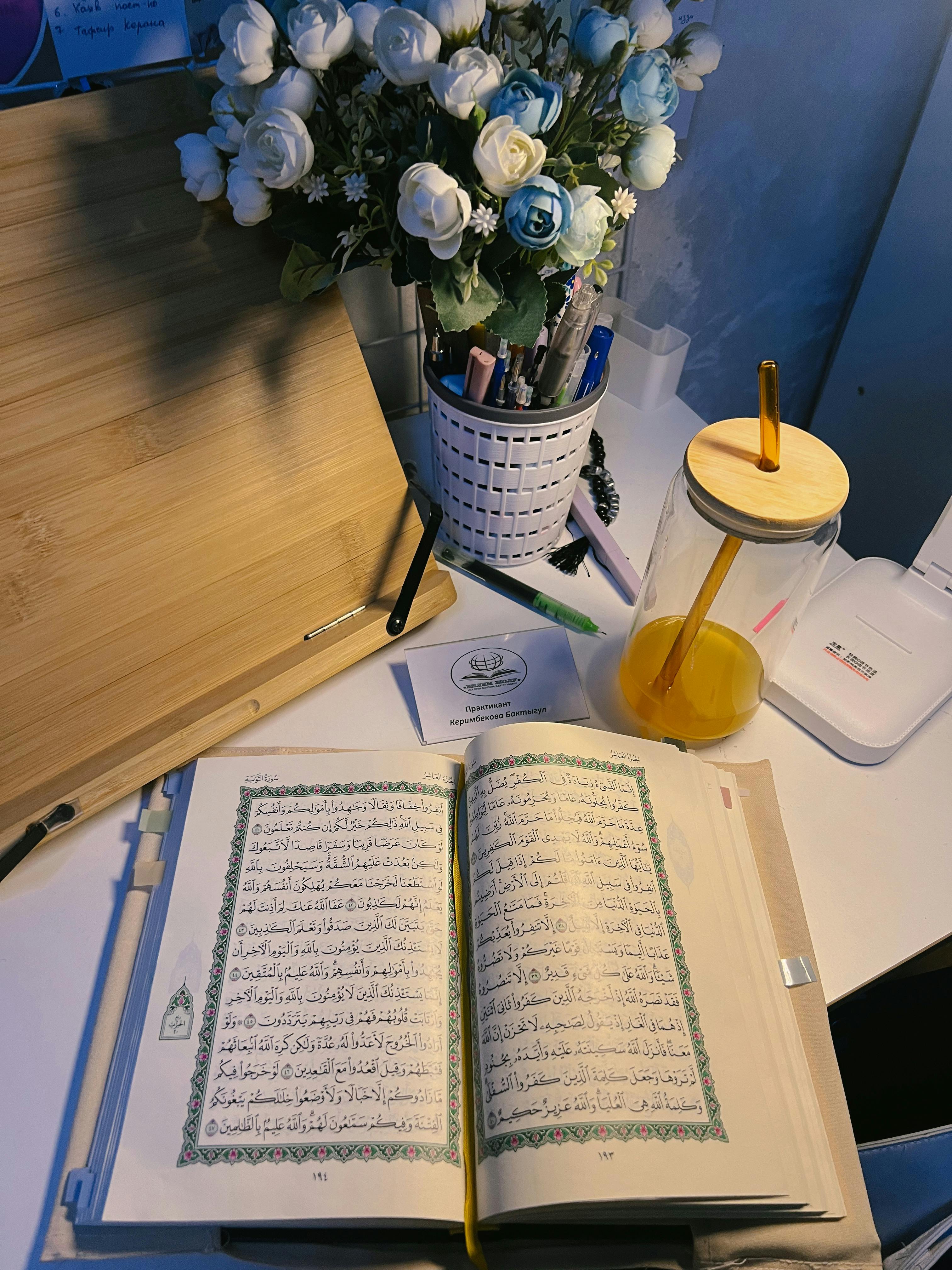 Open Quran with Desk Accessories and Floral Arrangement · Free Stock Photo