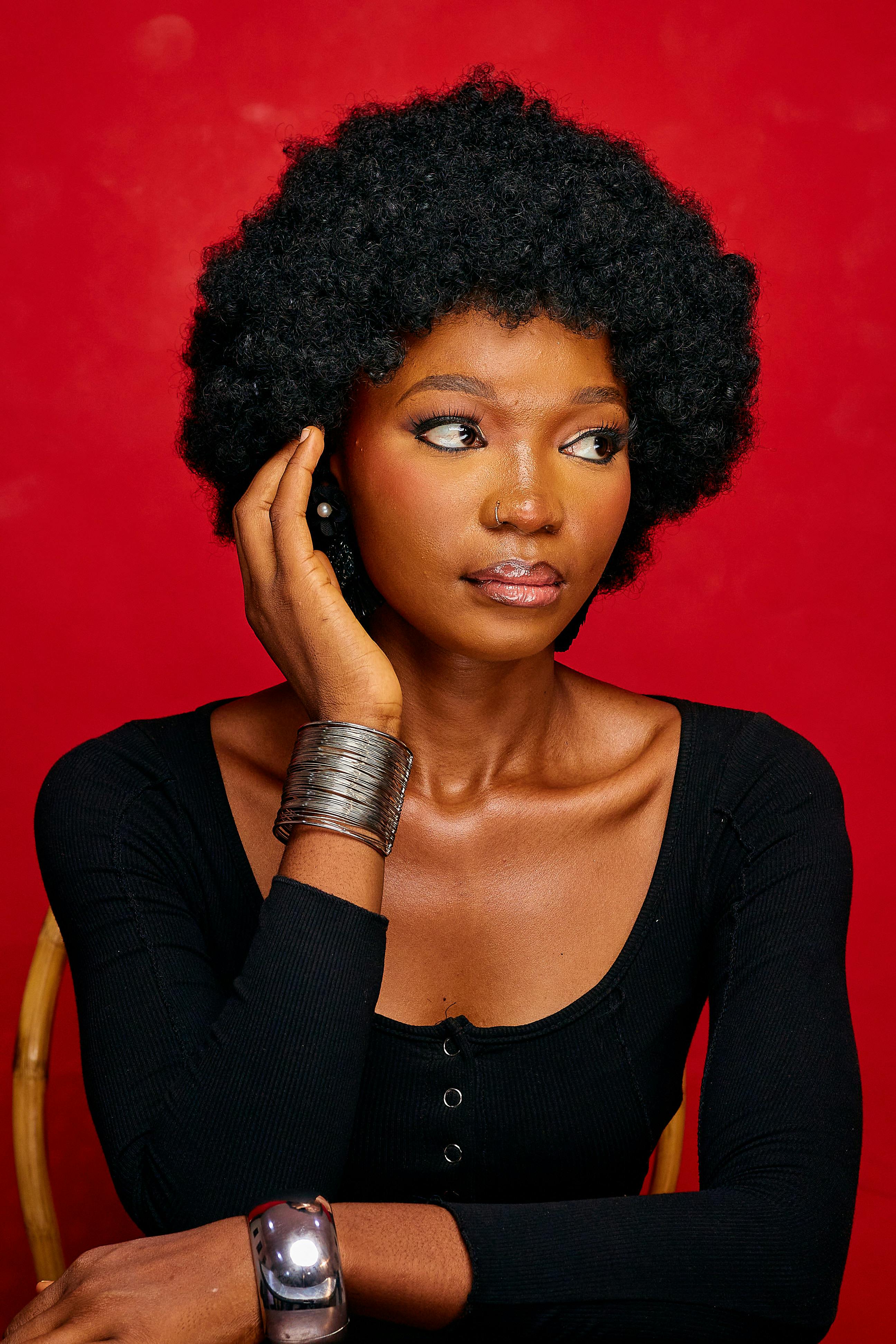 Elegant Woman with Afro Hairstyle and Red Backdrop · Free Stock Photo