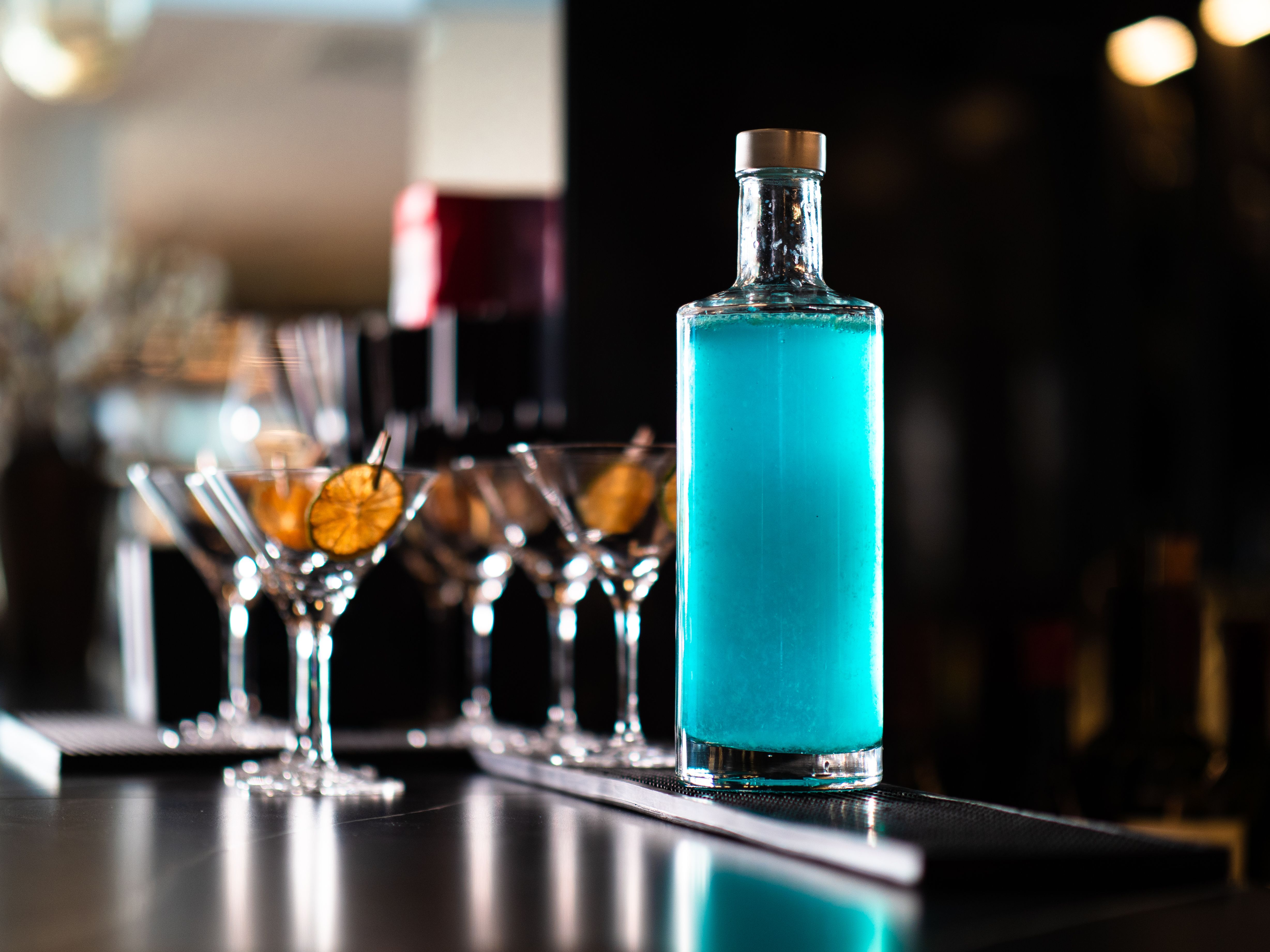 Vibrant Blue Cocktail Bottle Display in Bar · Free Stock Photo