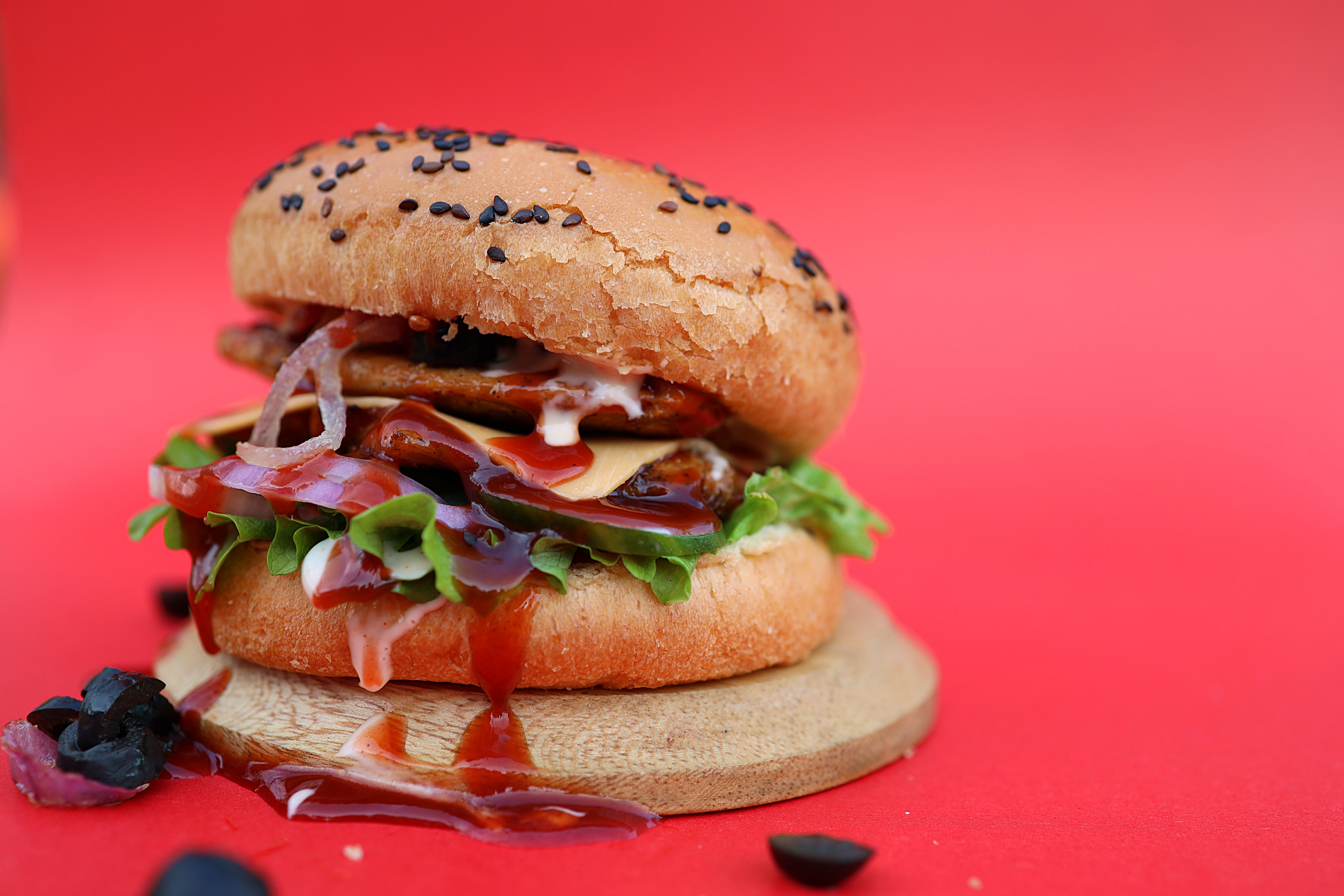 Juicy Burger with Dripping Sauce on Red Background · Free Stock Photo