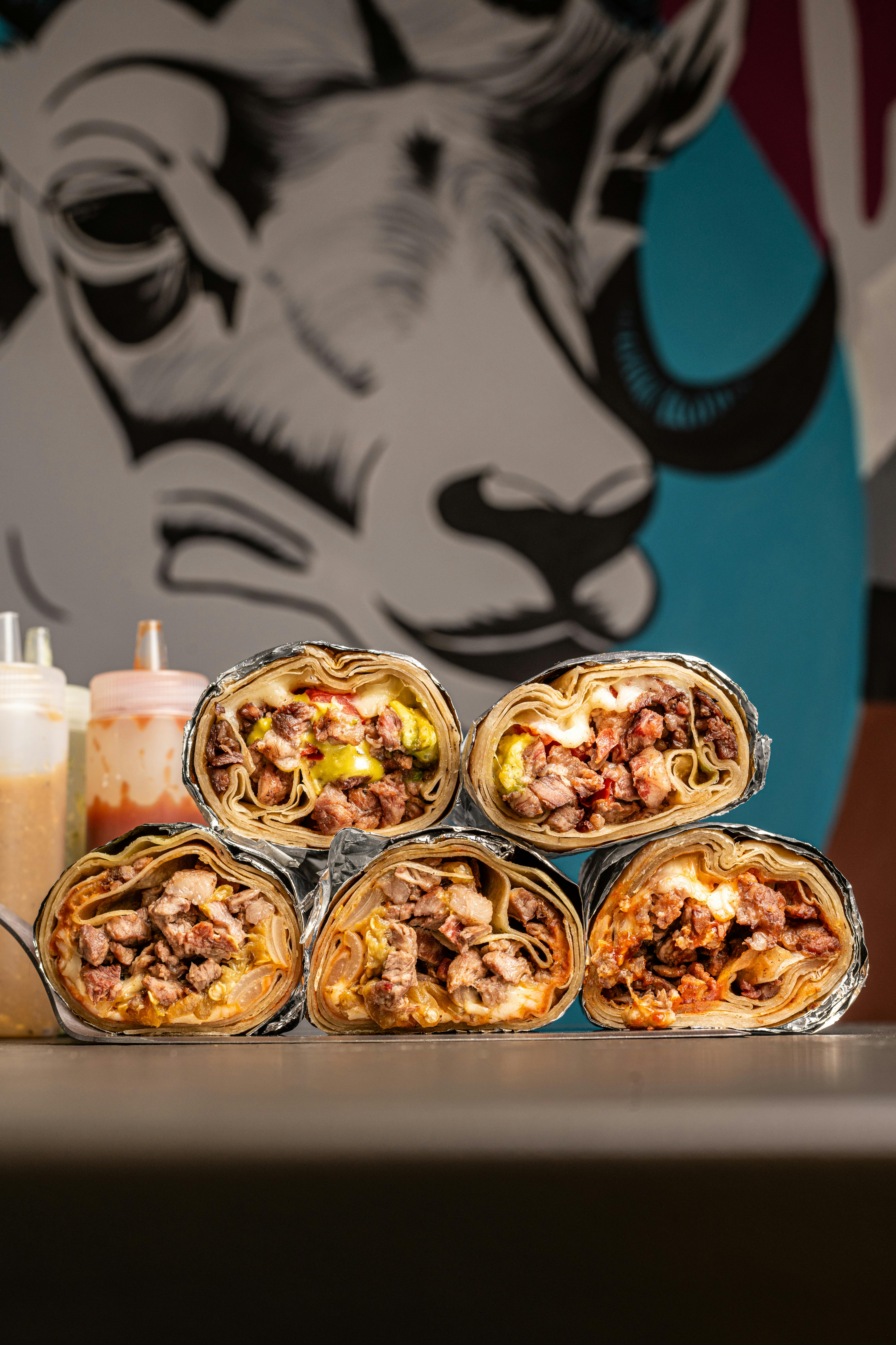 Delicious Stacked Burritos with Vibrant Mural · Free Stock Photo