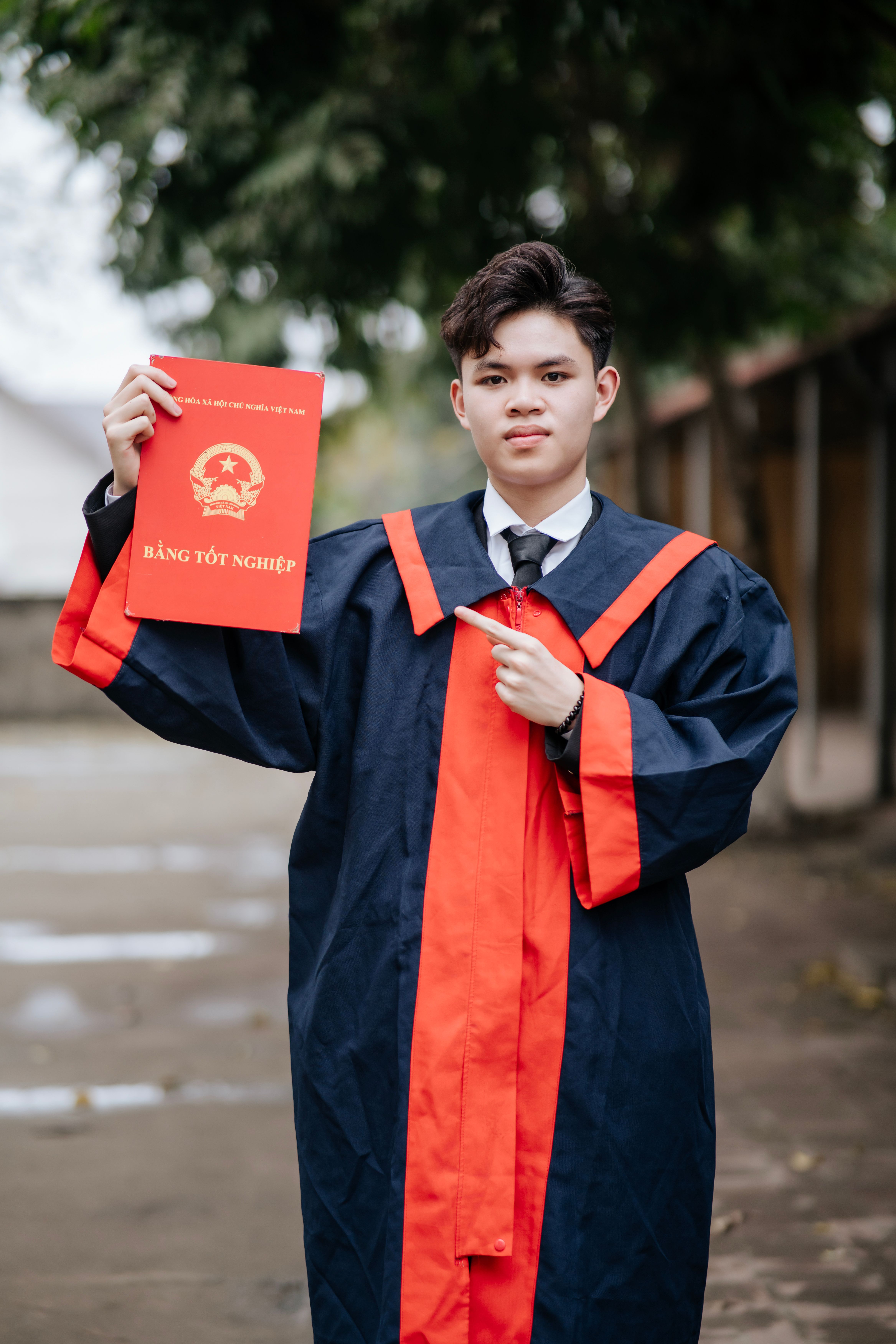 Young Graduate Holding Diploma Outdoors · Free Stock Photo