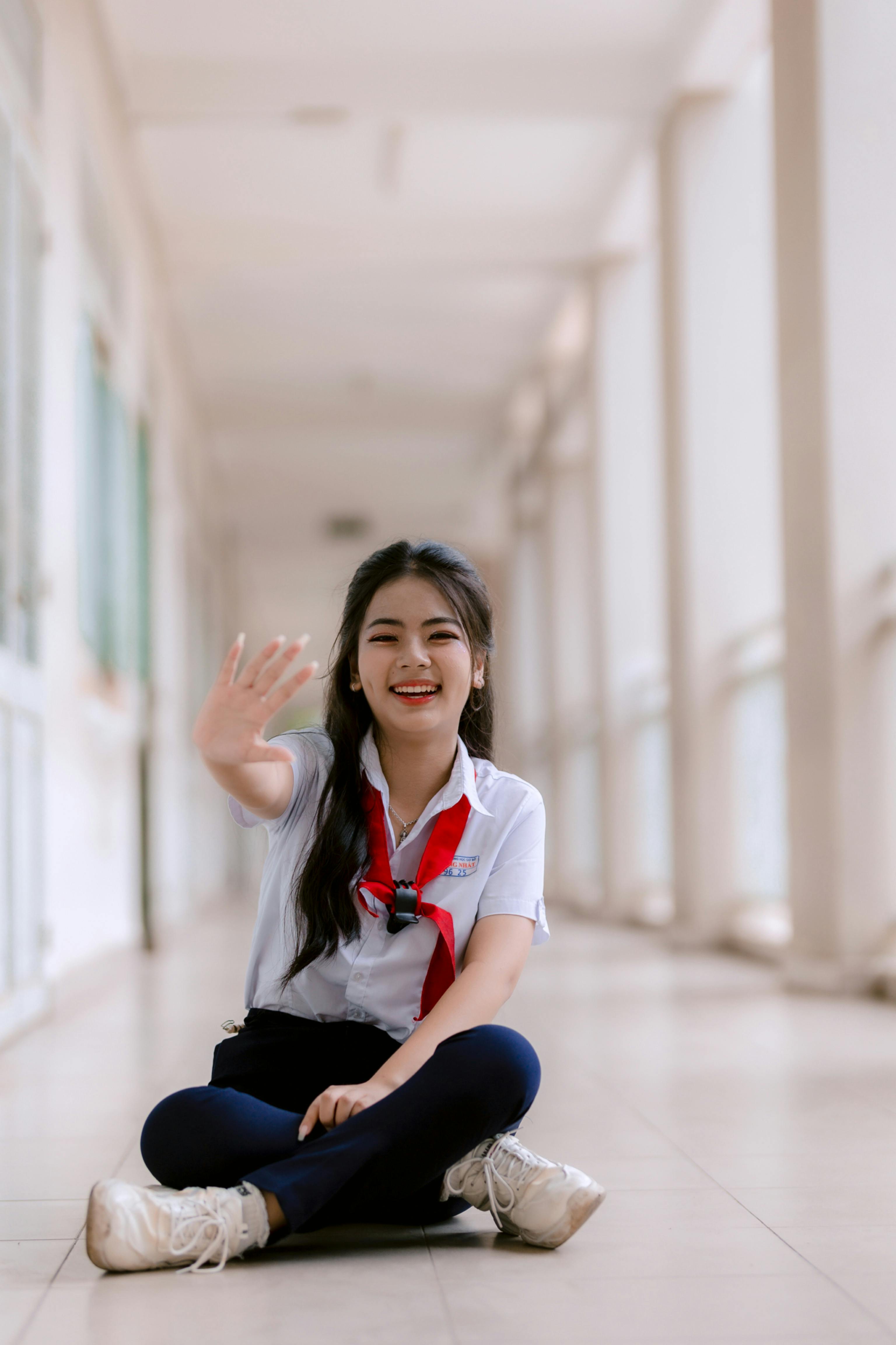 Smiling Student Waving in School Hallway · Free Stock Photo