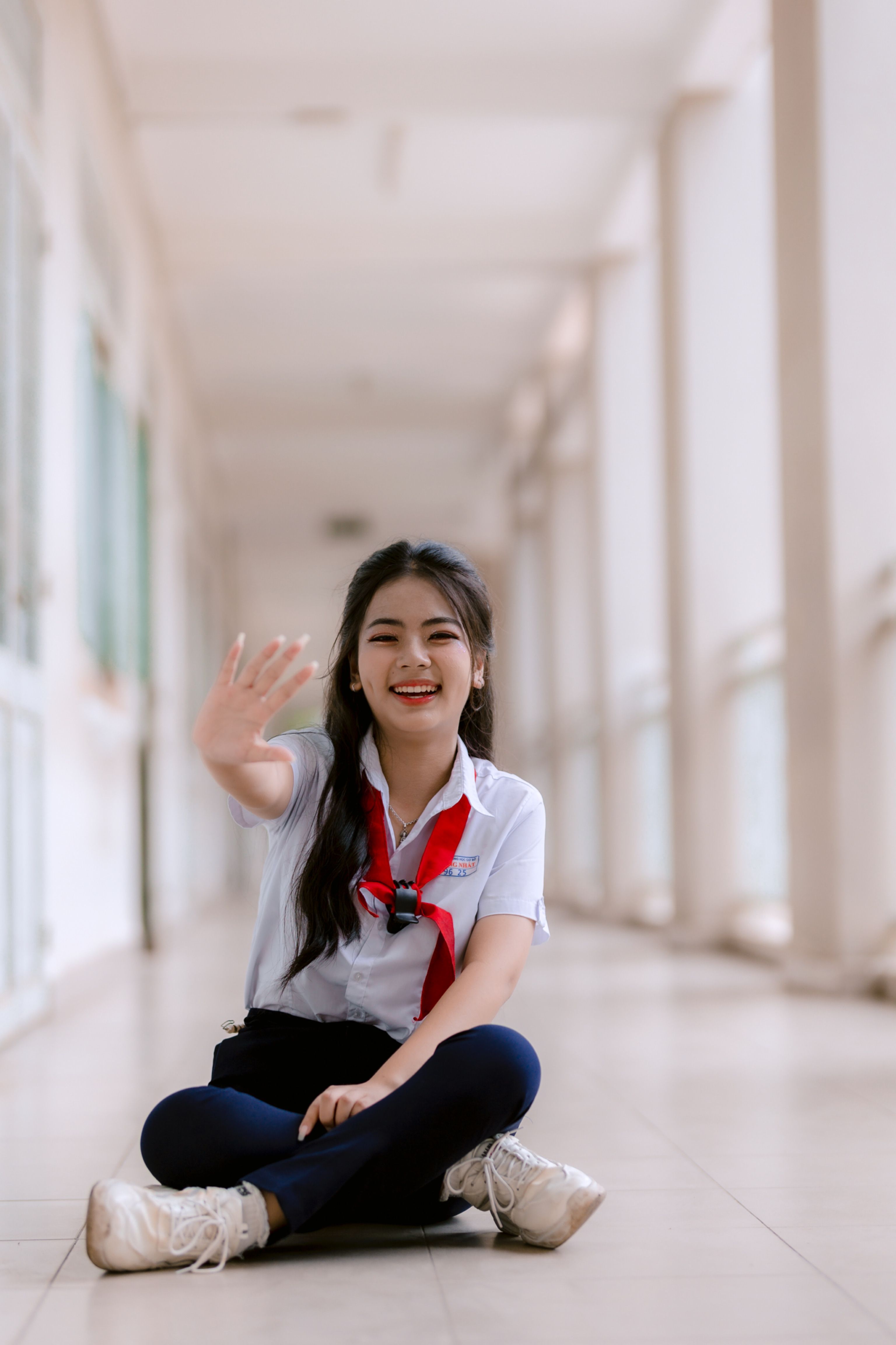 Smiling Student Waving in School Hallway · Free Stock Photo