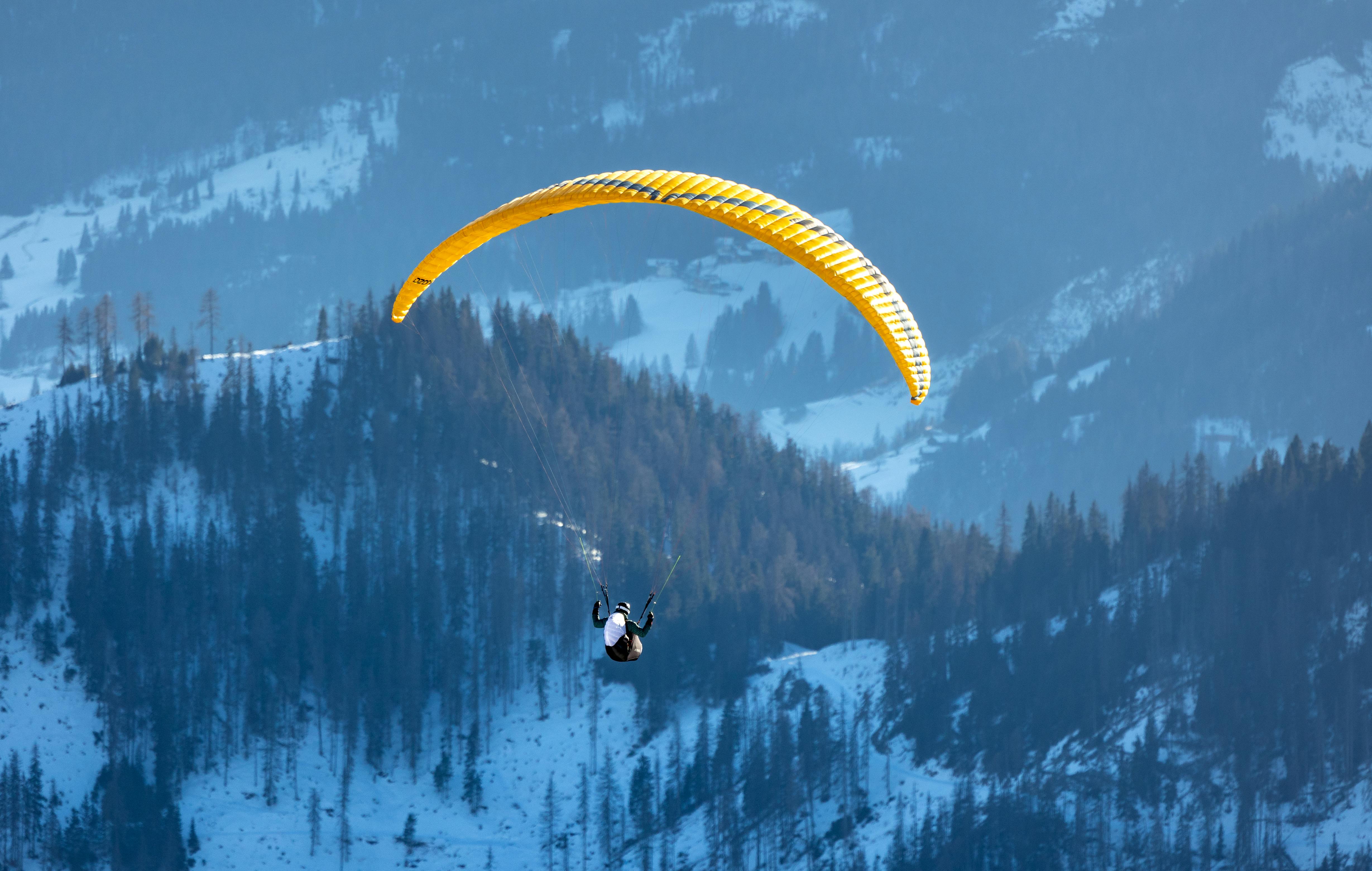 Paraglider Soaring Over Snowy Dolomites in Winter · Free Stock Photo