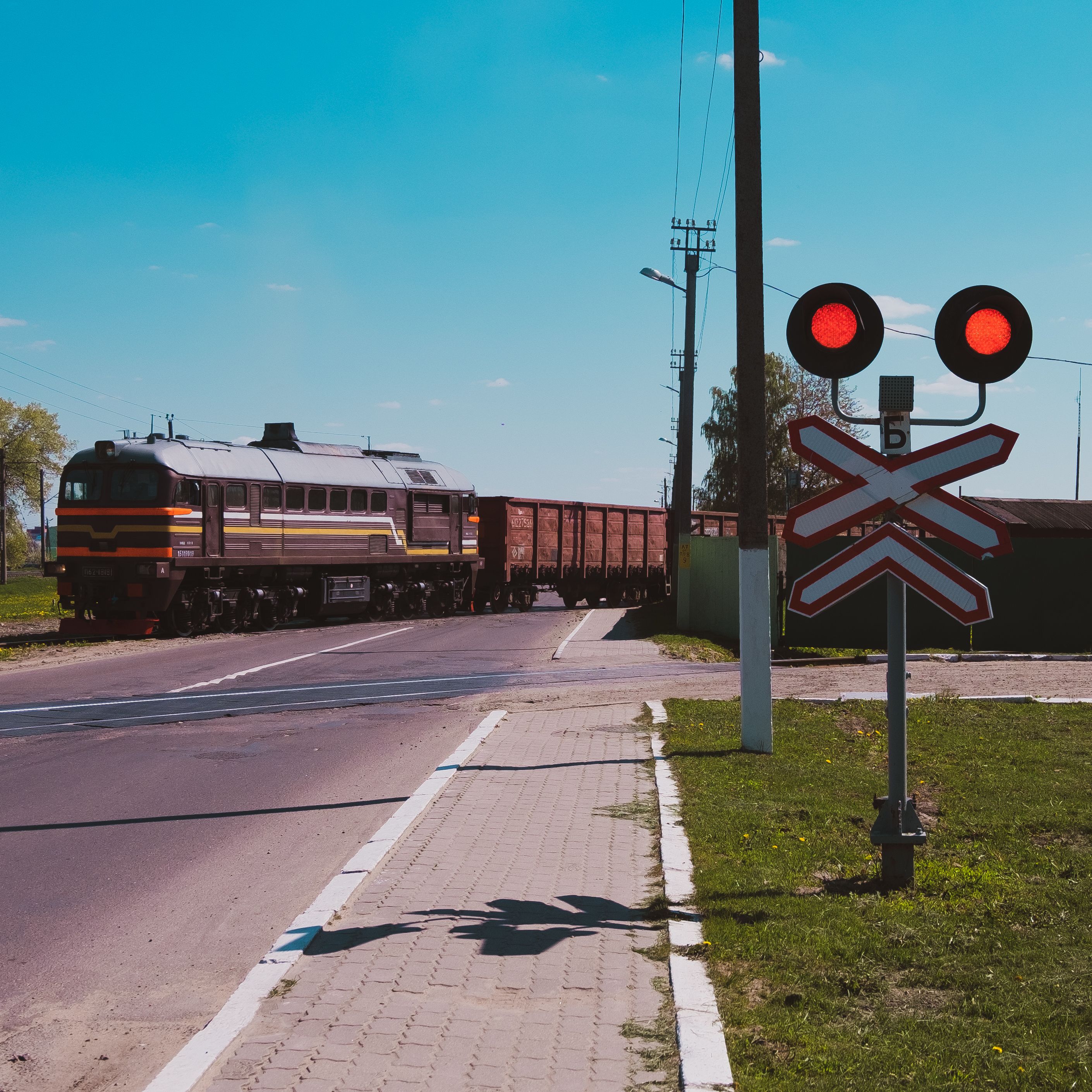 Train Crossing Road with Signal Lights on a Sunny Day · Free Stock Photo