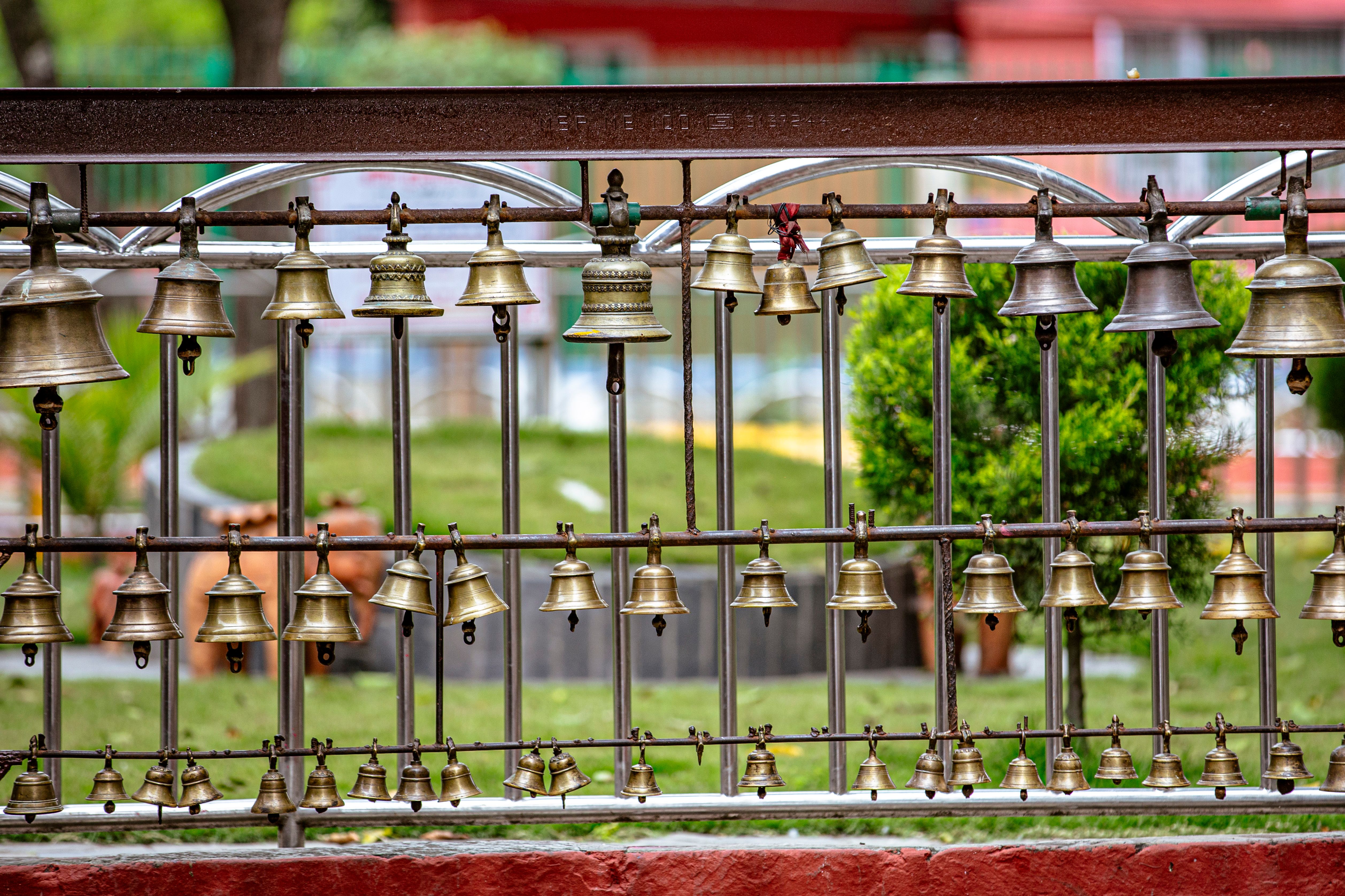 Ornate Brass Bells on Outdoor Metal Railing · Free Stock Photo