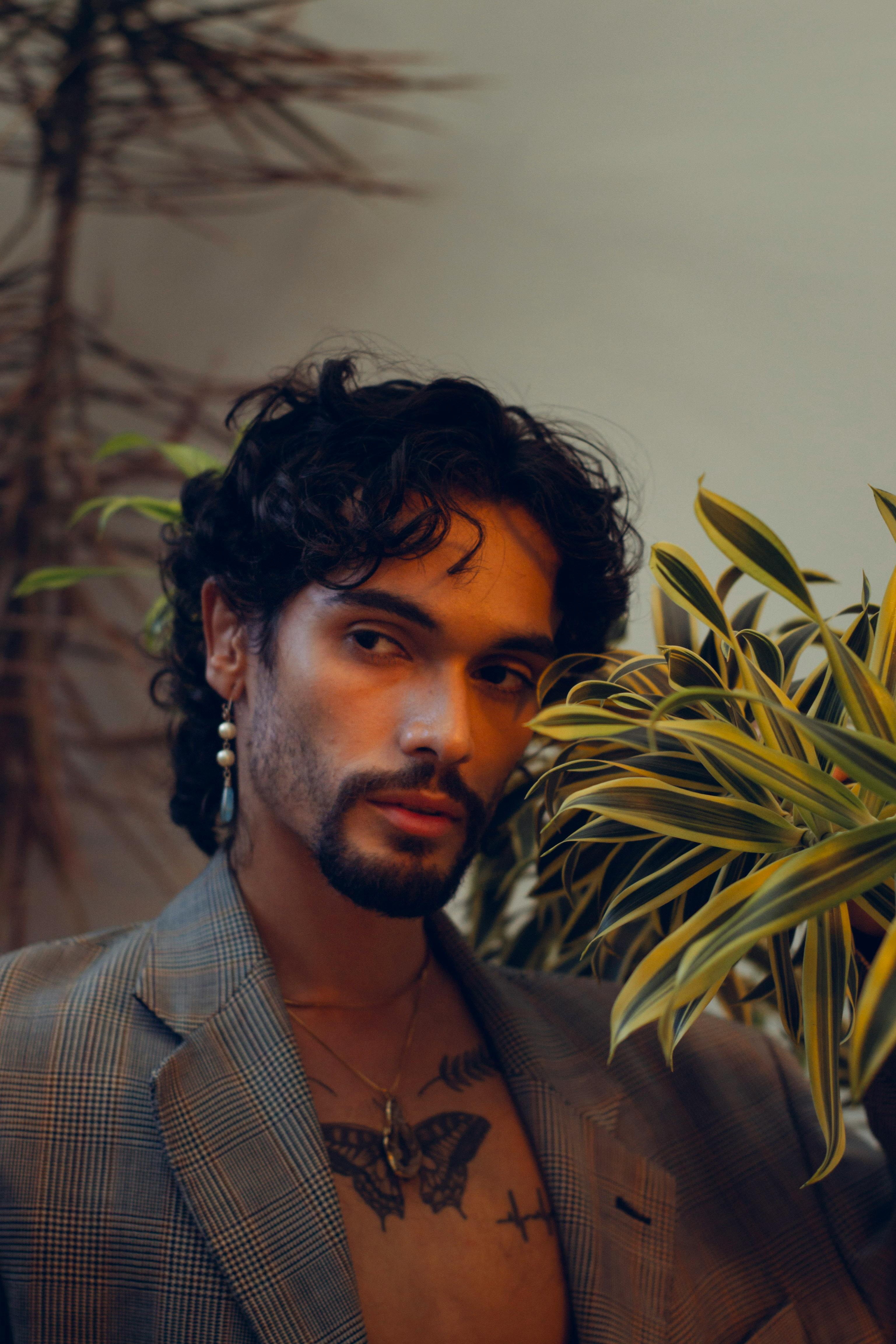 Stylish Portrait of a Man with Curly Hair and Tattoos · Free Stock Photo