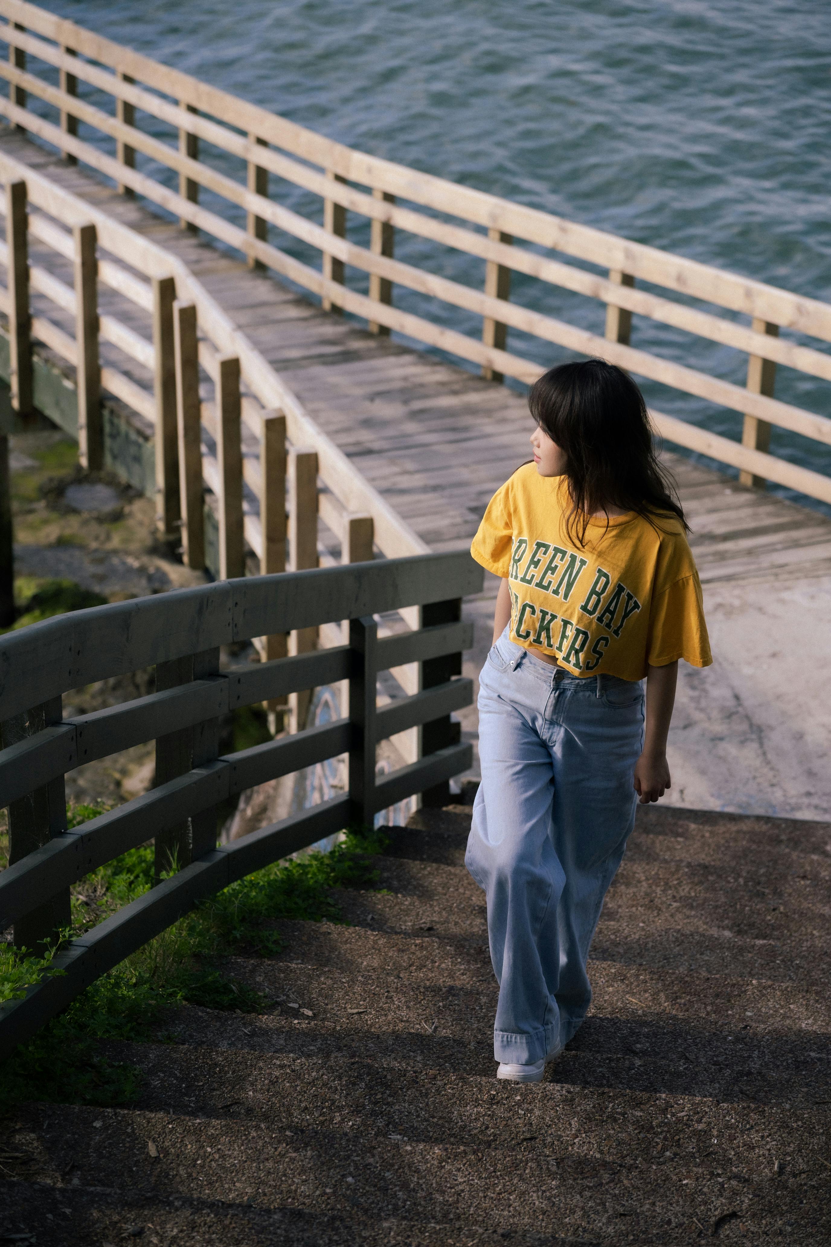 Young Woman Walking on Scenic Lakeside Boardwalk · Free Stock Photo