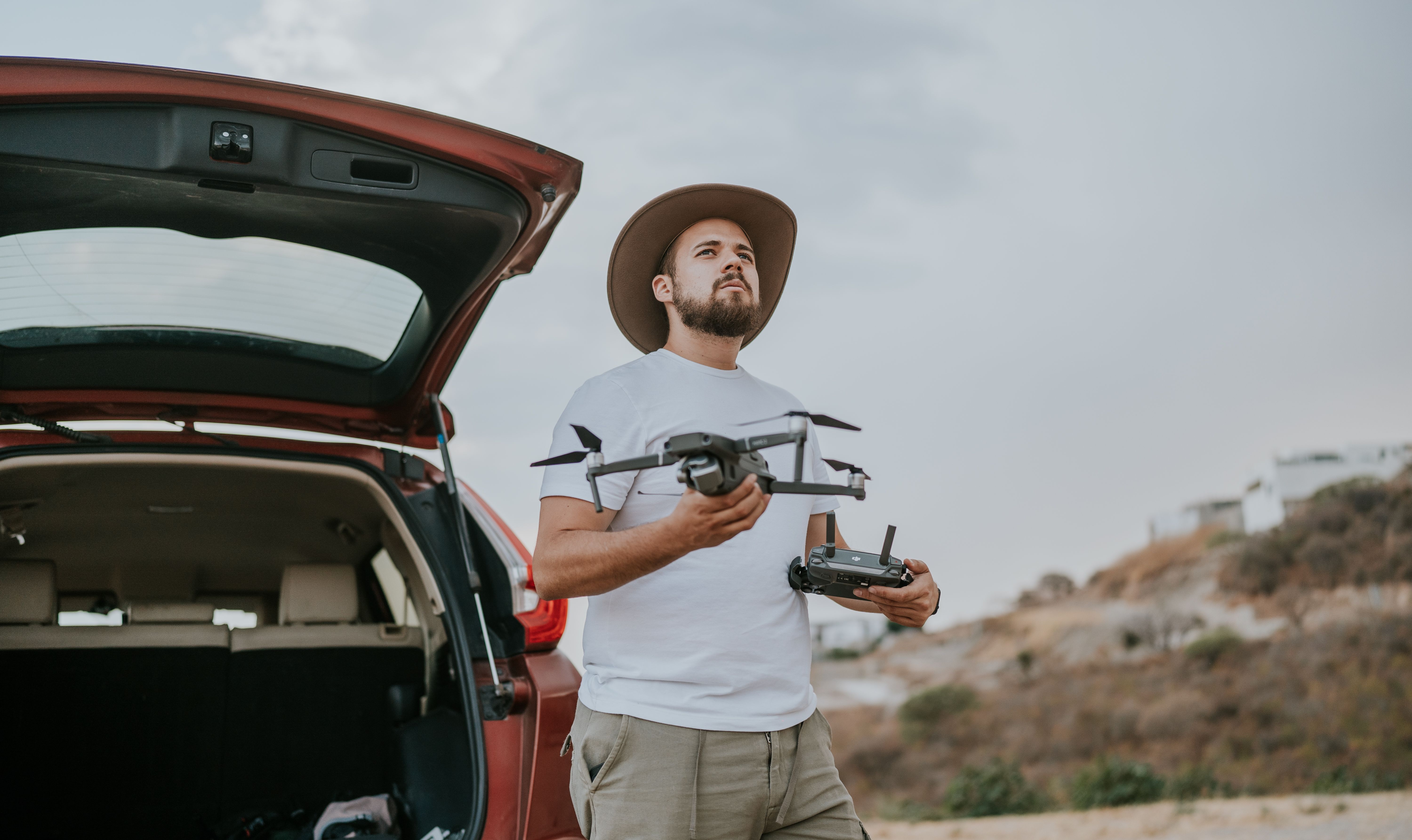 Man with Drone Preparing for Flight Outdoors · Free Stock Photo