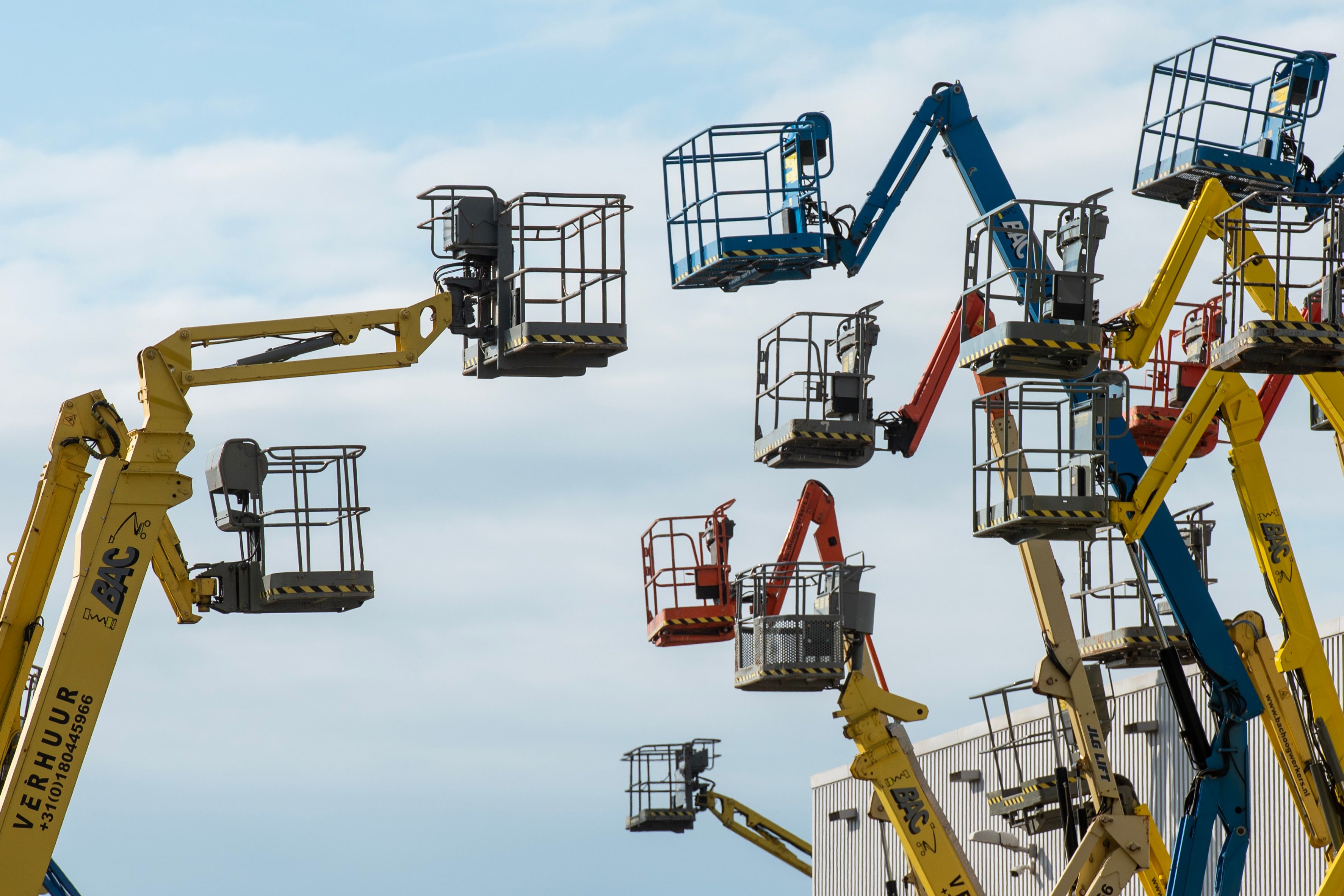 Colorful Boom Lifts Against Blue Sky · Free Stock Photo