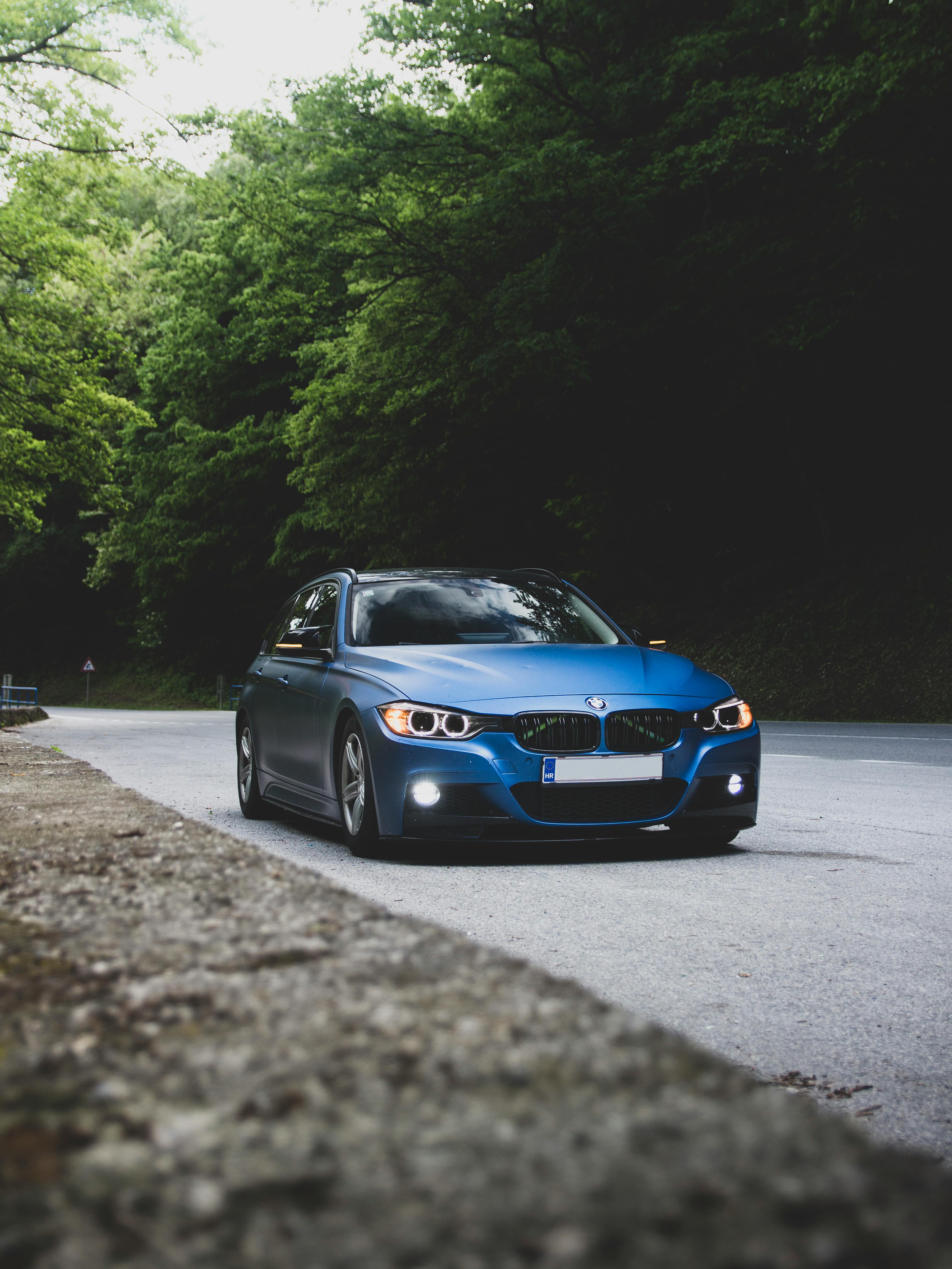 Blue Luxury Car on Scenic Forest Road · Free Stock Photo