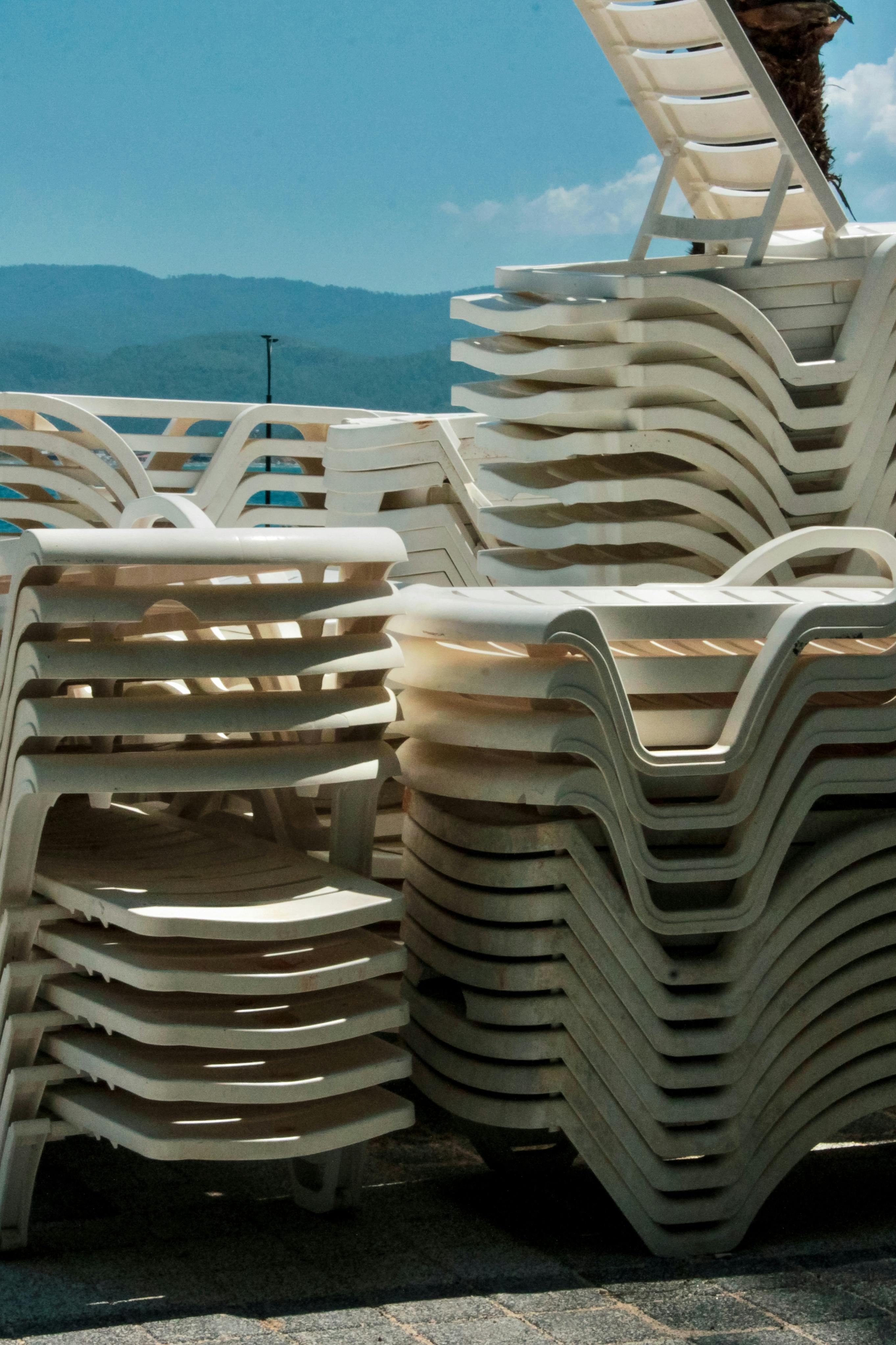 Stacked Plastic Chairs Outdoors on Sunny Day · Free Stock Photo