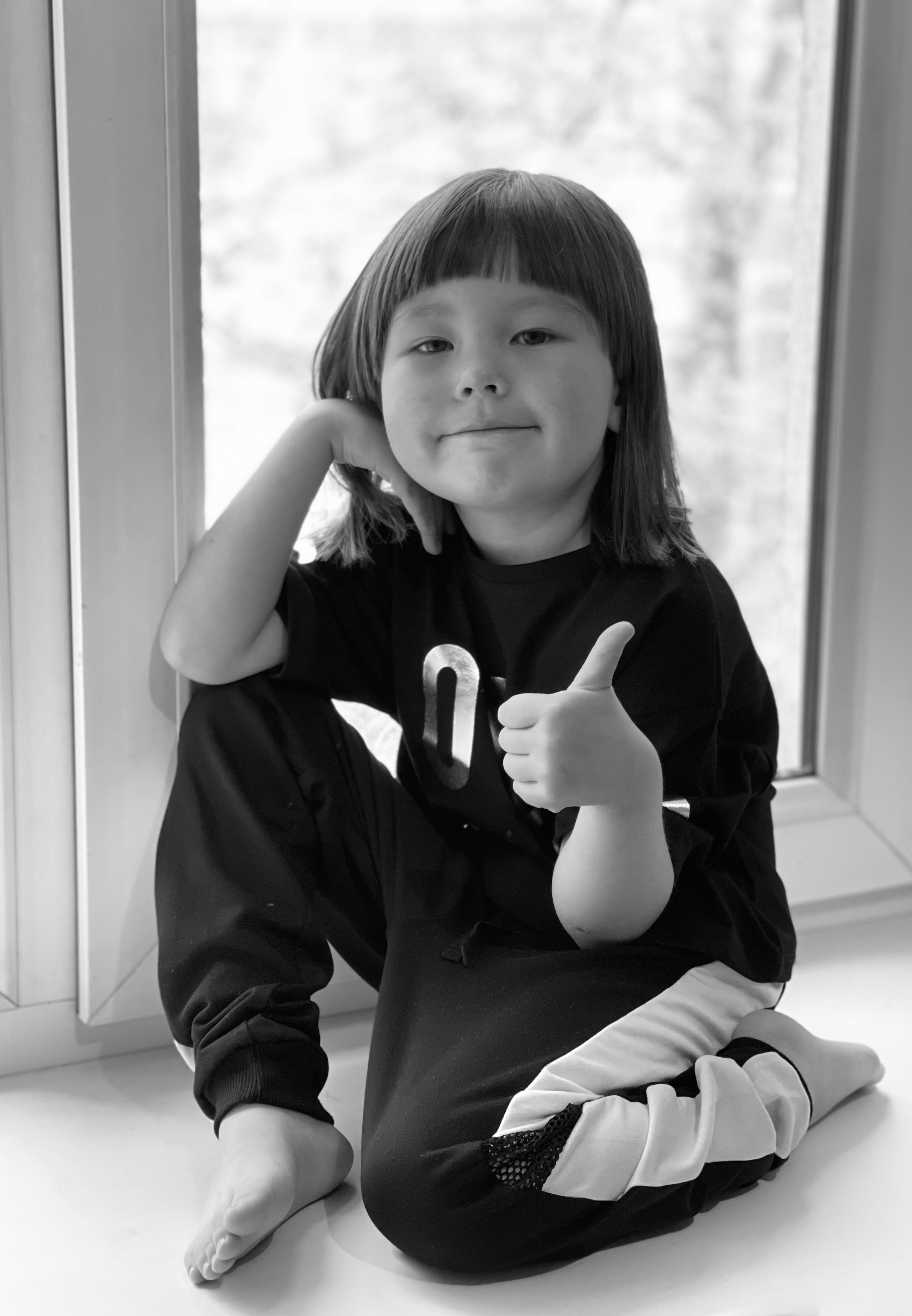 Child posing with thumbs up near window · Free Stock Photo