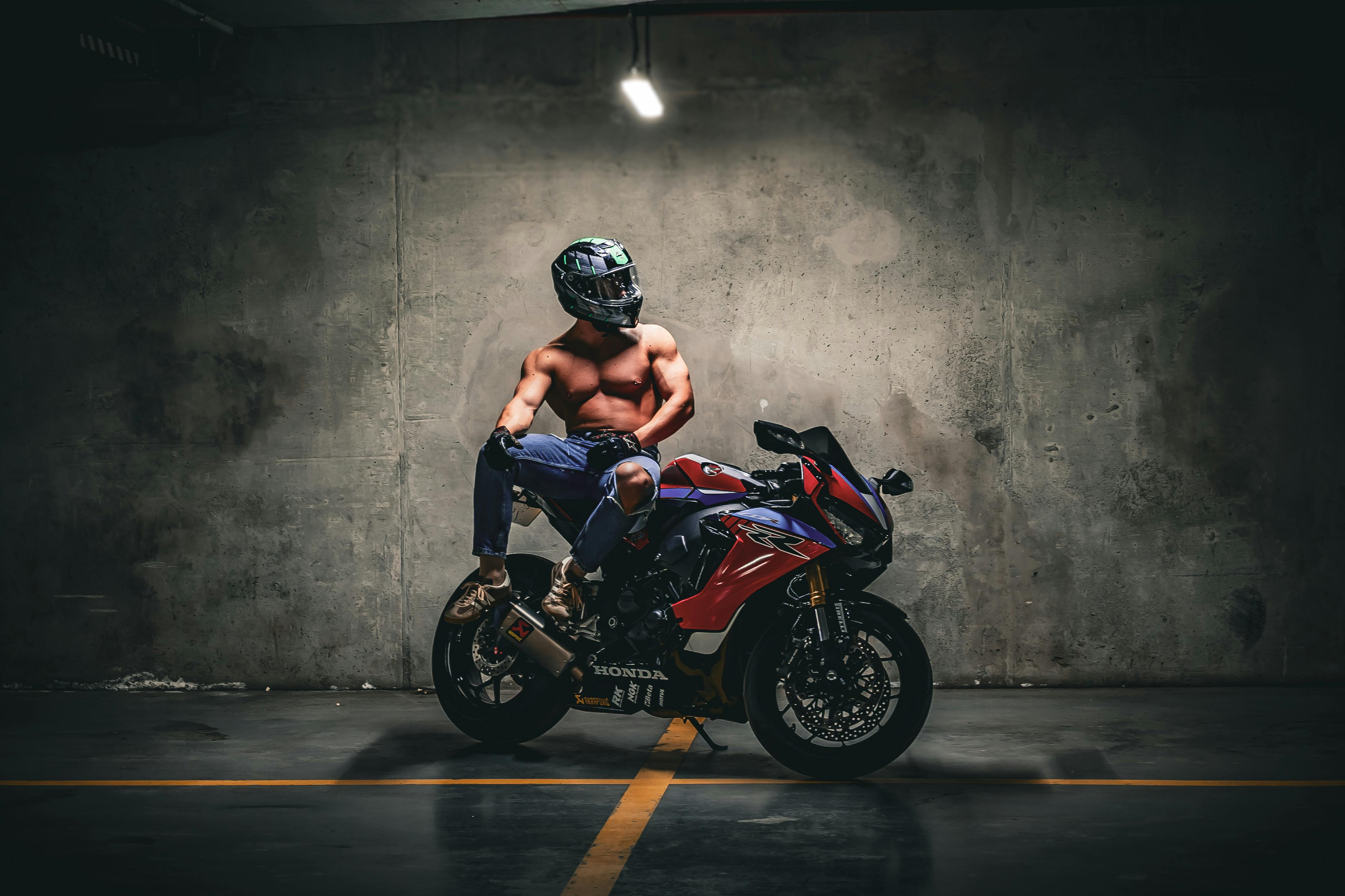 Muscular Man Posing on Motorcycle in Garage · Free Stock Photo