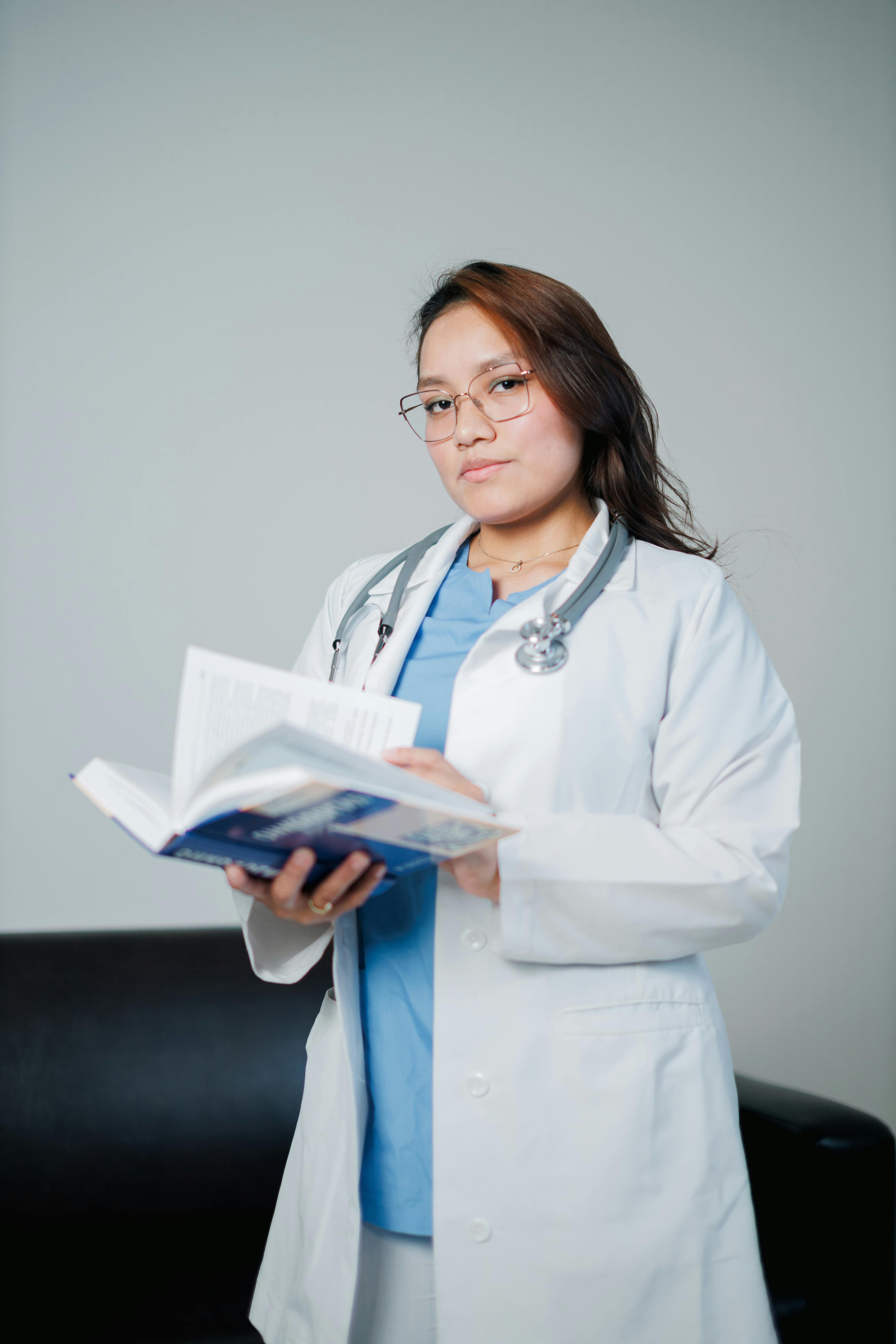 Female Doctor Reading a Medical Book Indoors · Free Stock Photo